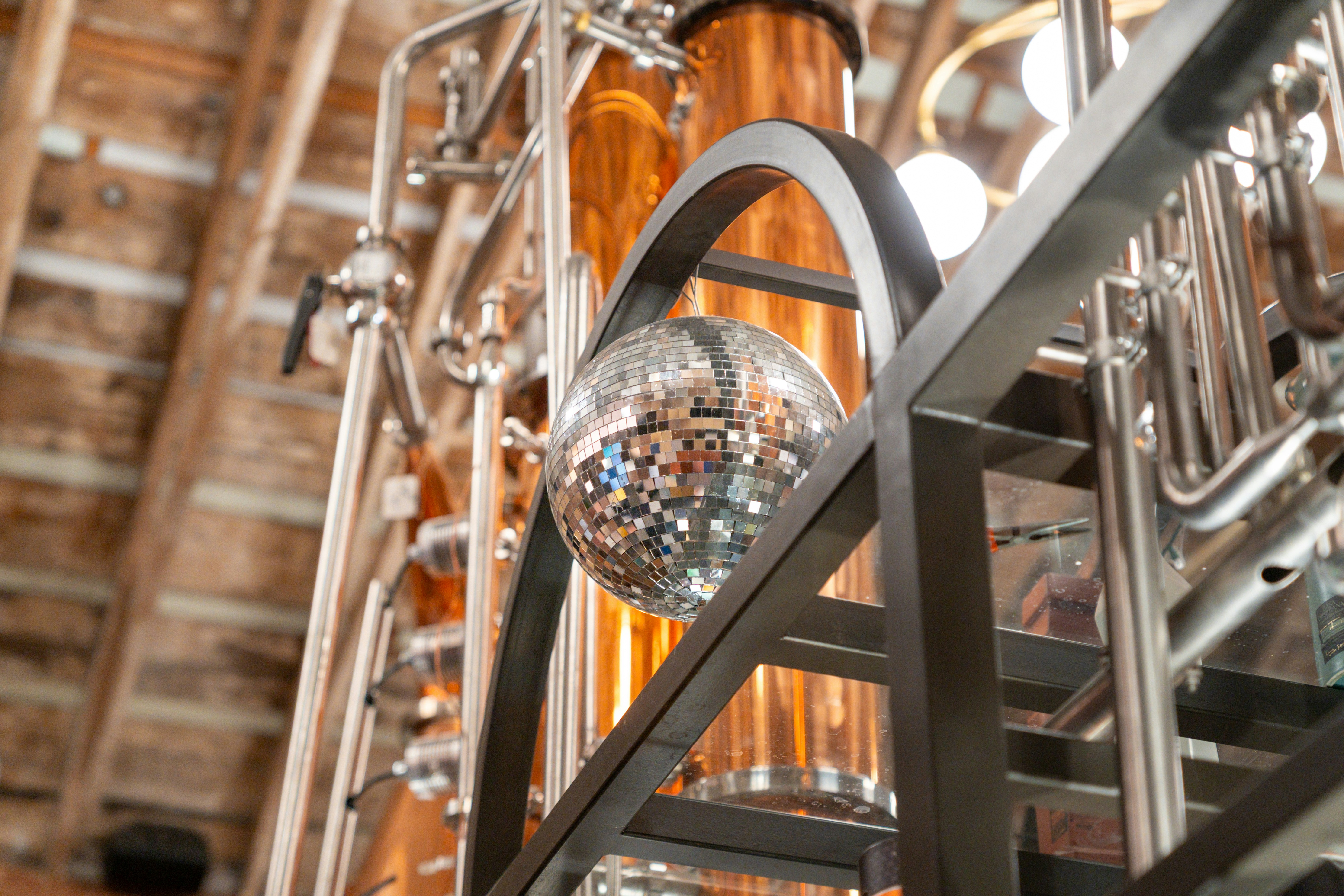 Polished Orbit: a gleaming disco sphere among industrial glass and copper pipes