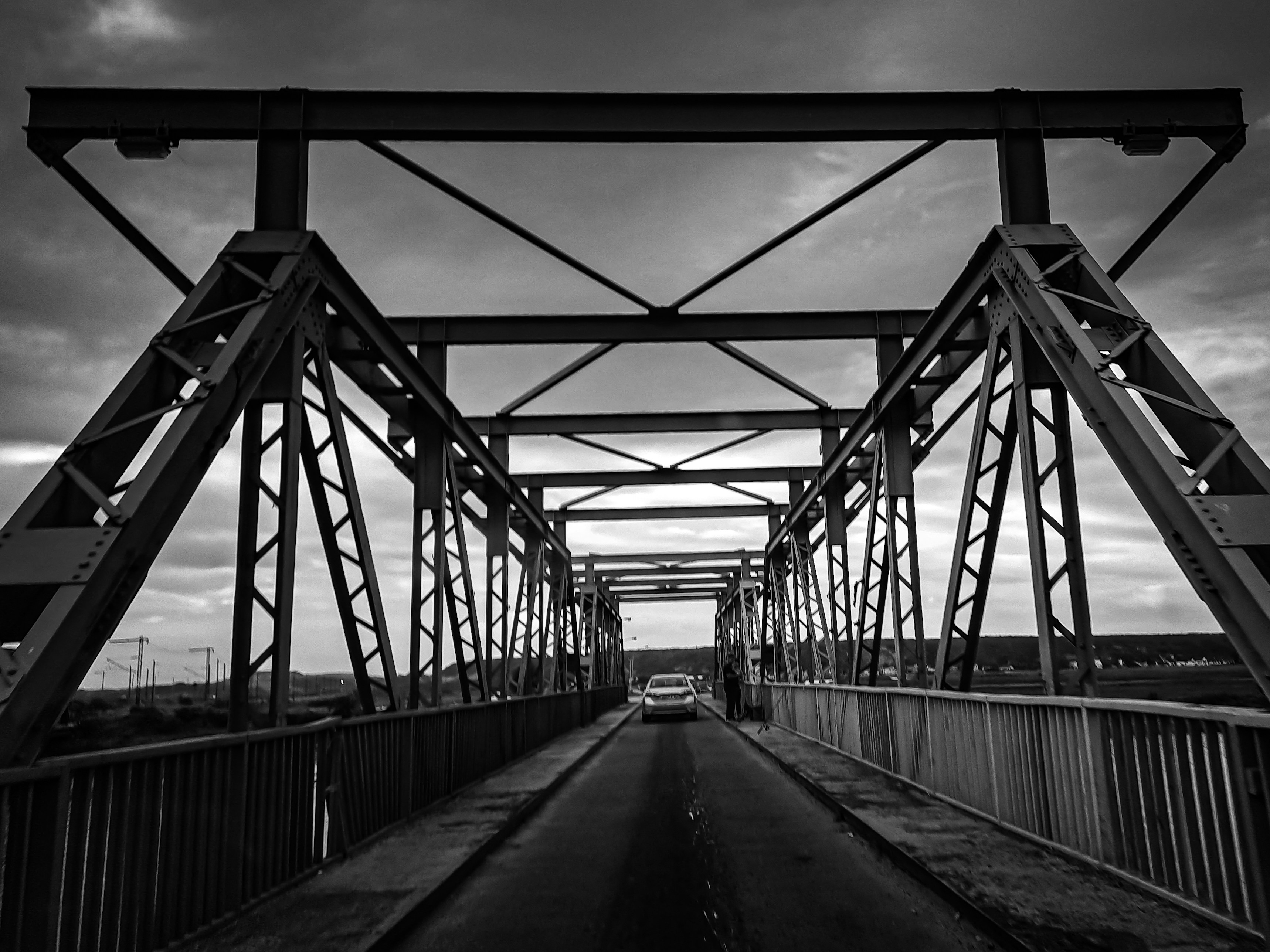 Symmetry on Steel: A Lone Car and Pedestrian Crossing the Truss Bridge