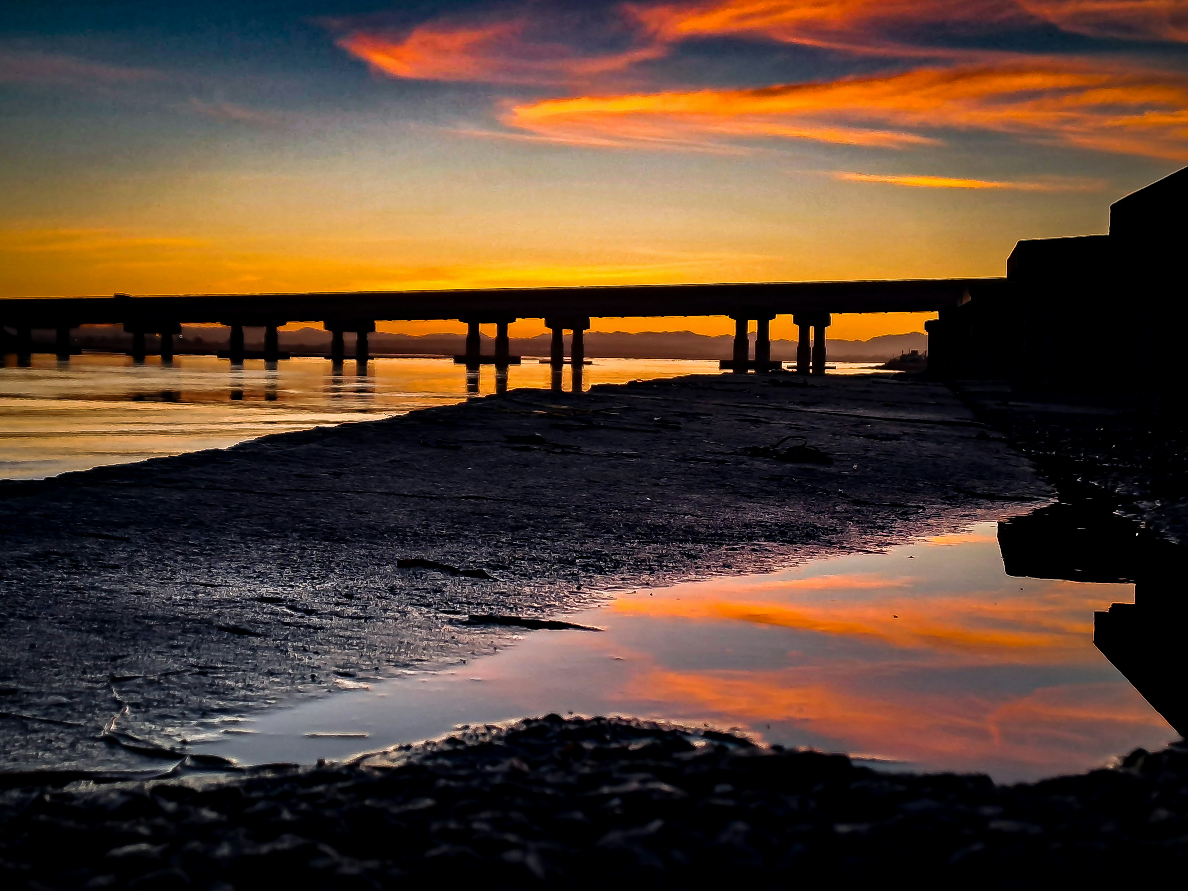 Sunset Slip: Pier Silhouettes and Fiery Reflections