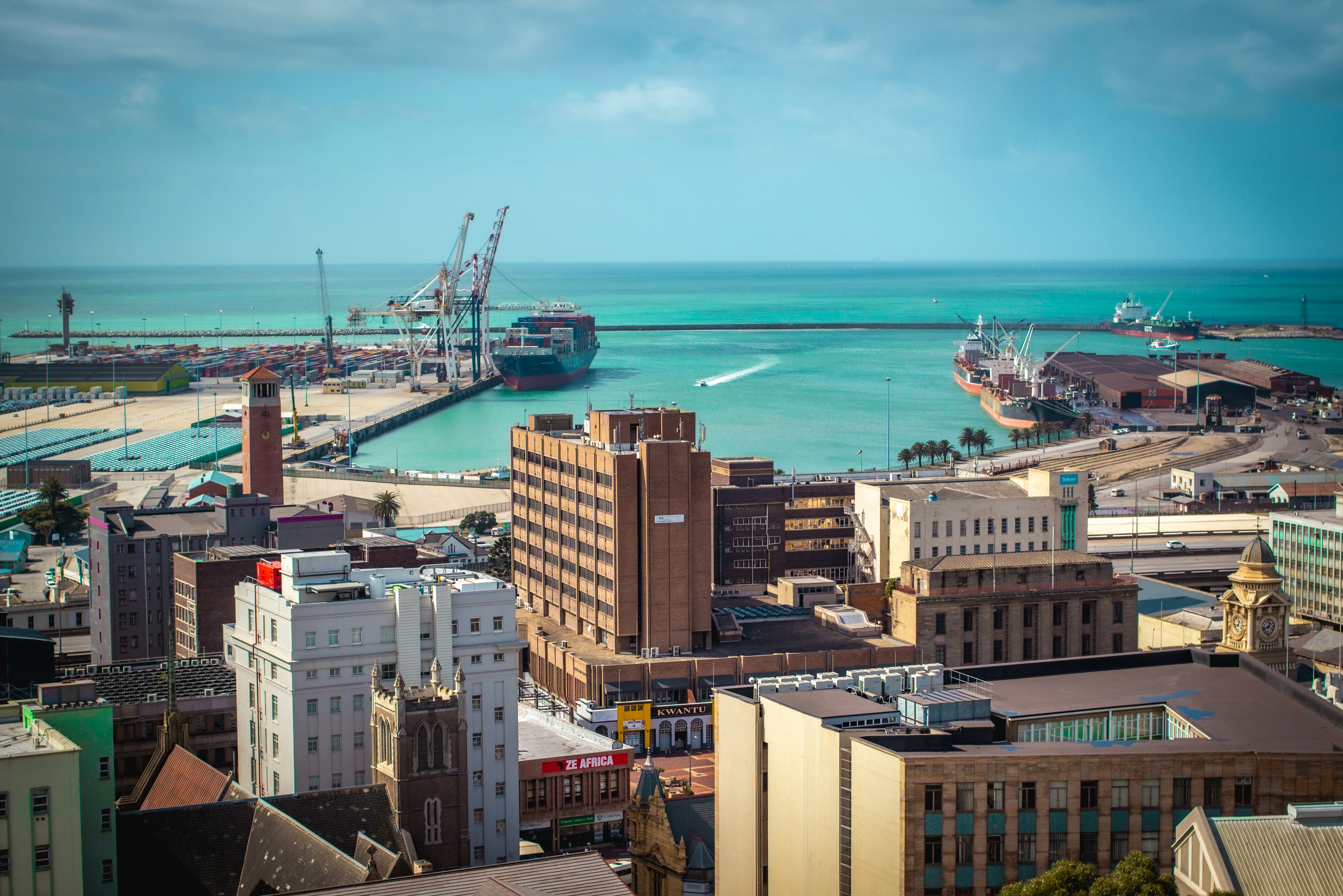 Harbor Cityscape: Cranes, docks, and turquoise water near a sunlit skyline