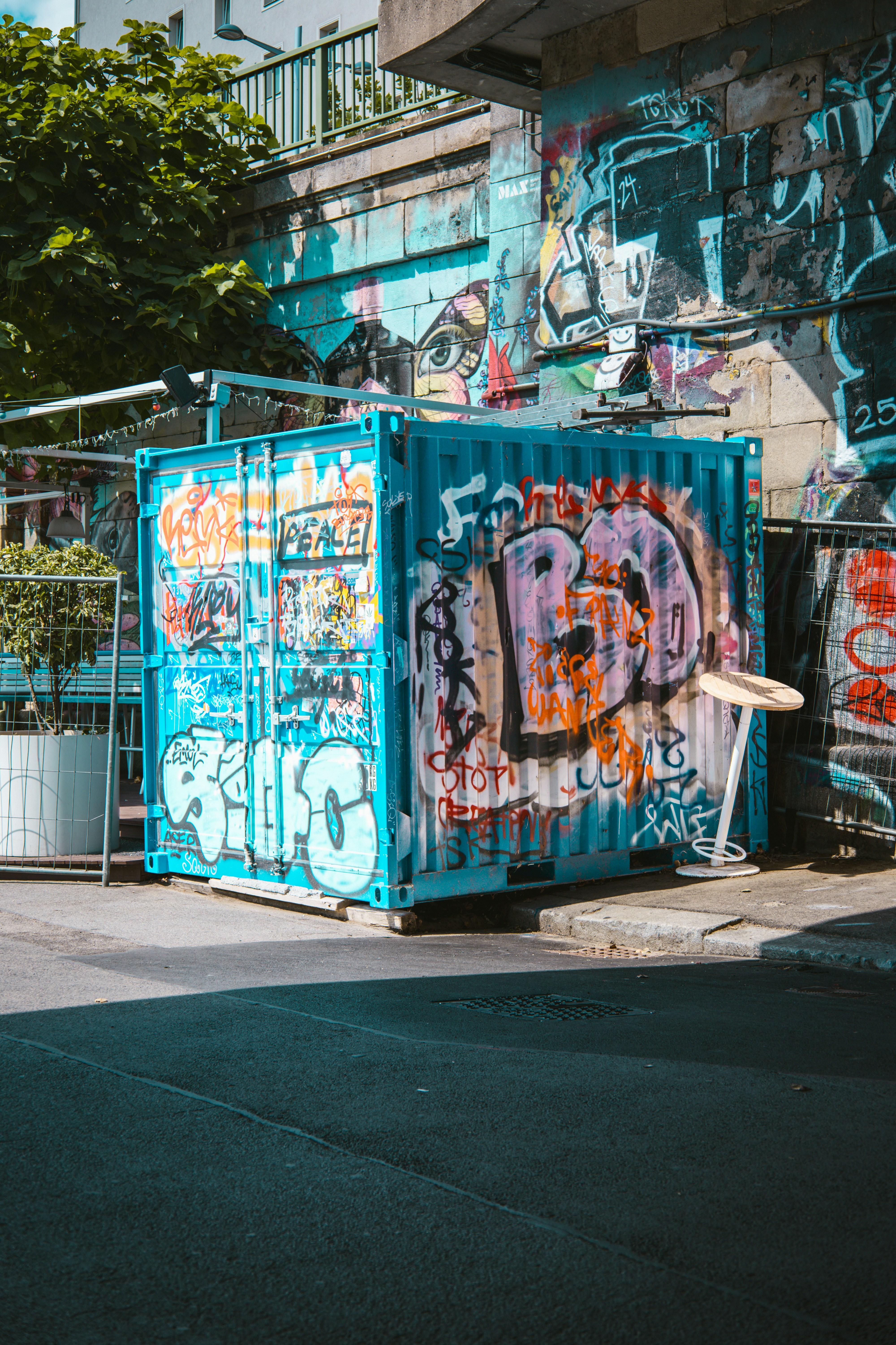 Graffiti Shipments: A Bright Blue Dumpster Against Urban Art Backdrop