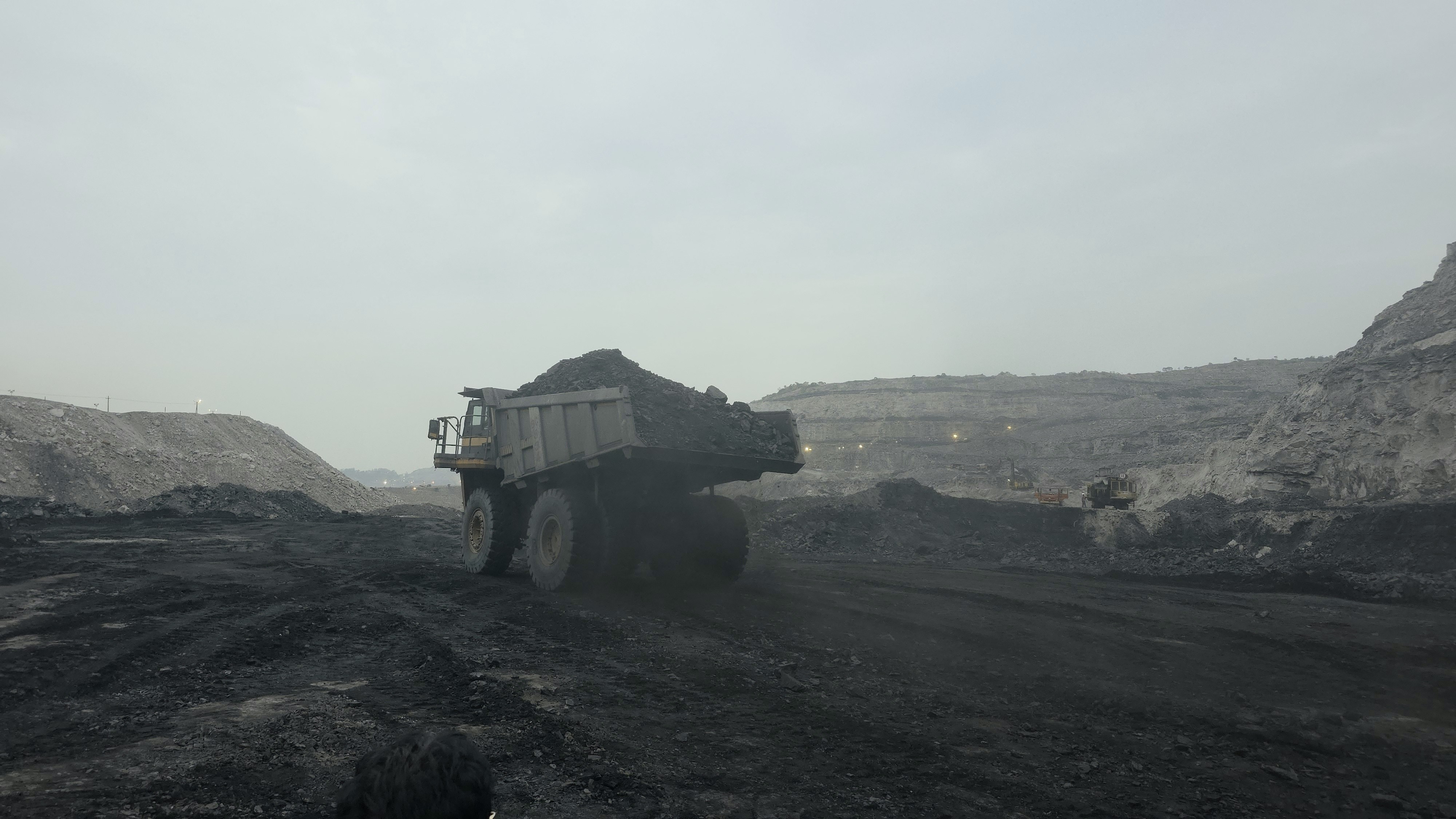 A striking view of a coal mining site showcasing rugged terrain, exposed rock, industrial structures, and the scale of mining operations.