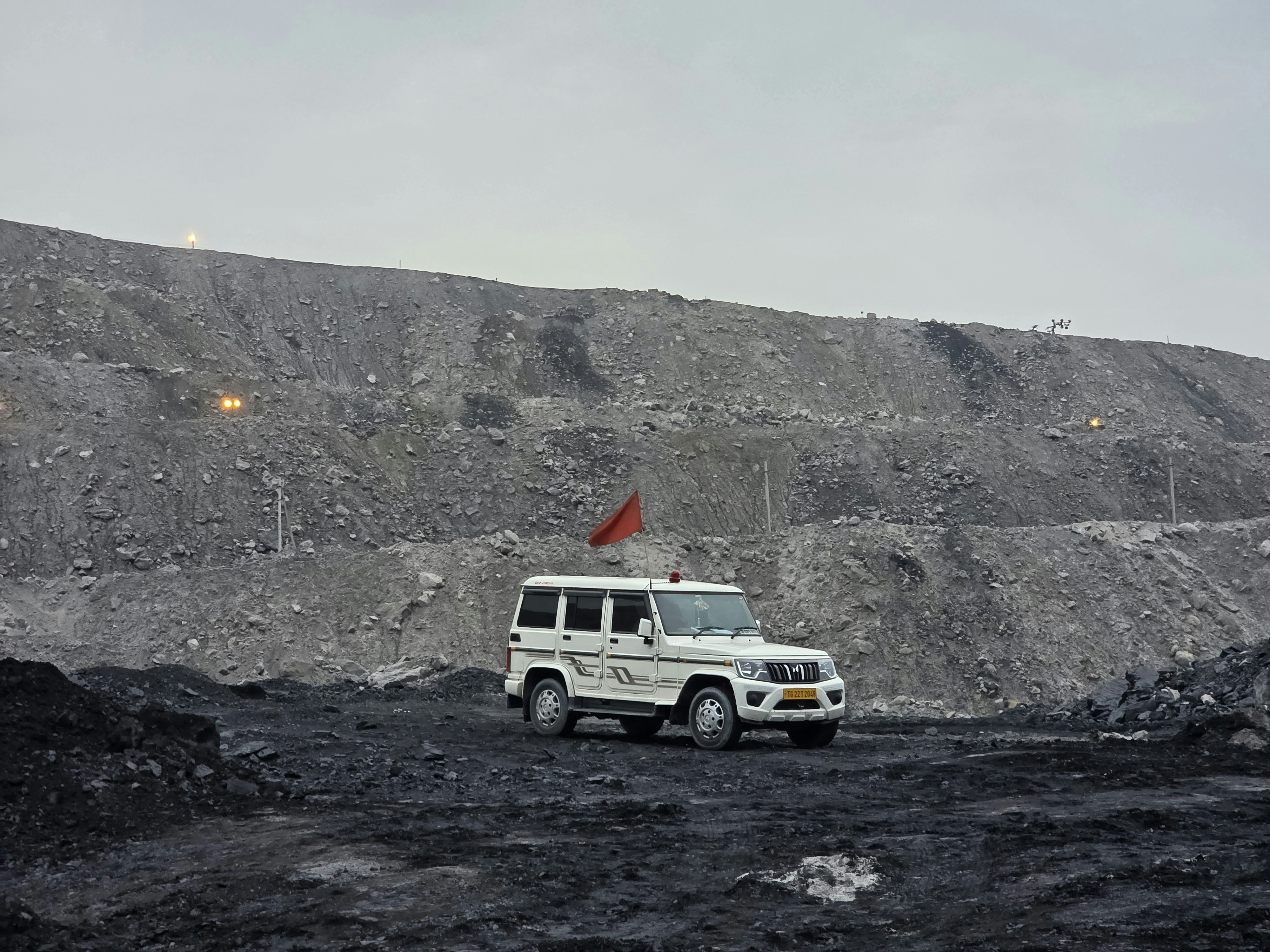 Rugged Explorer: White SUV with Red Flag Anchored in a Coal Quarry