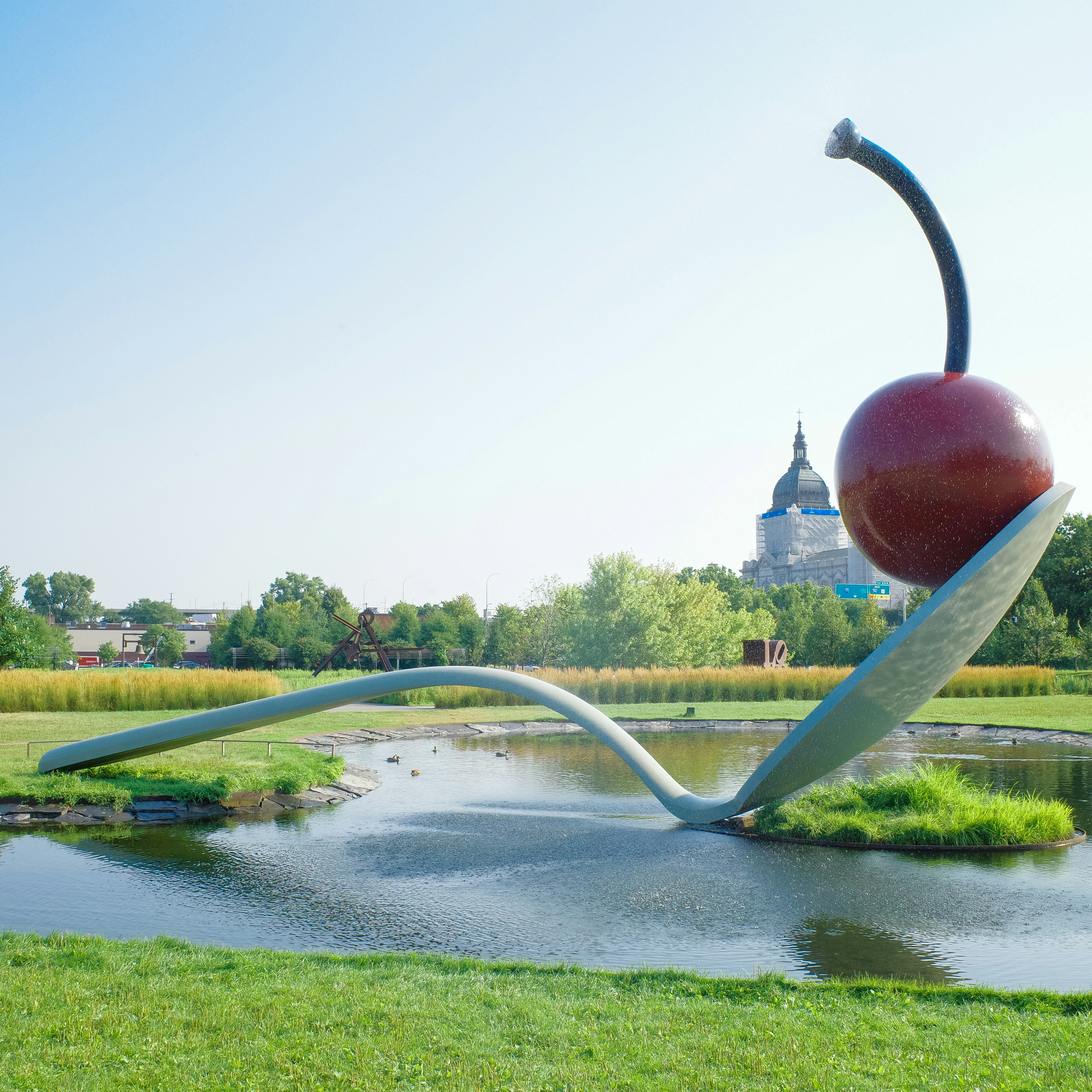 Whimsical Cherry on a Steel Spoon in a Serene Park