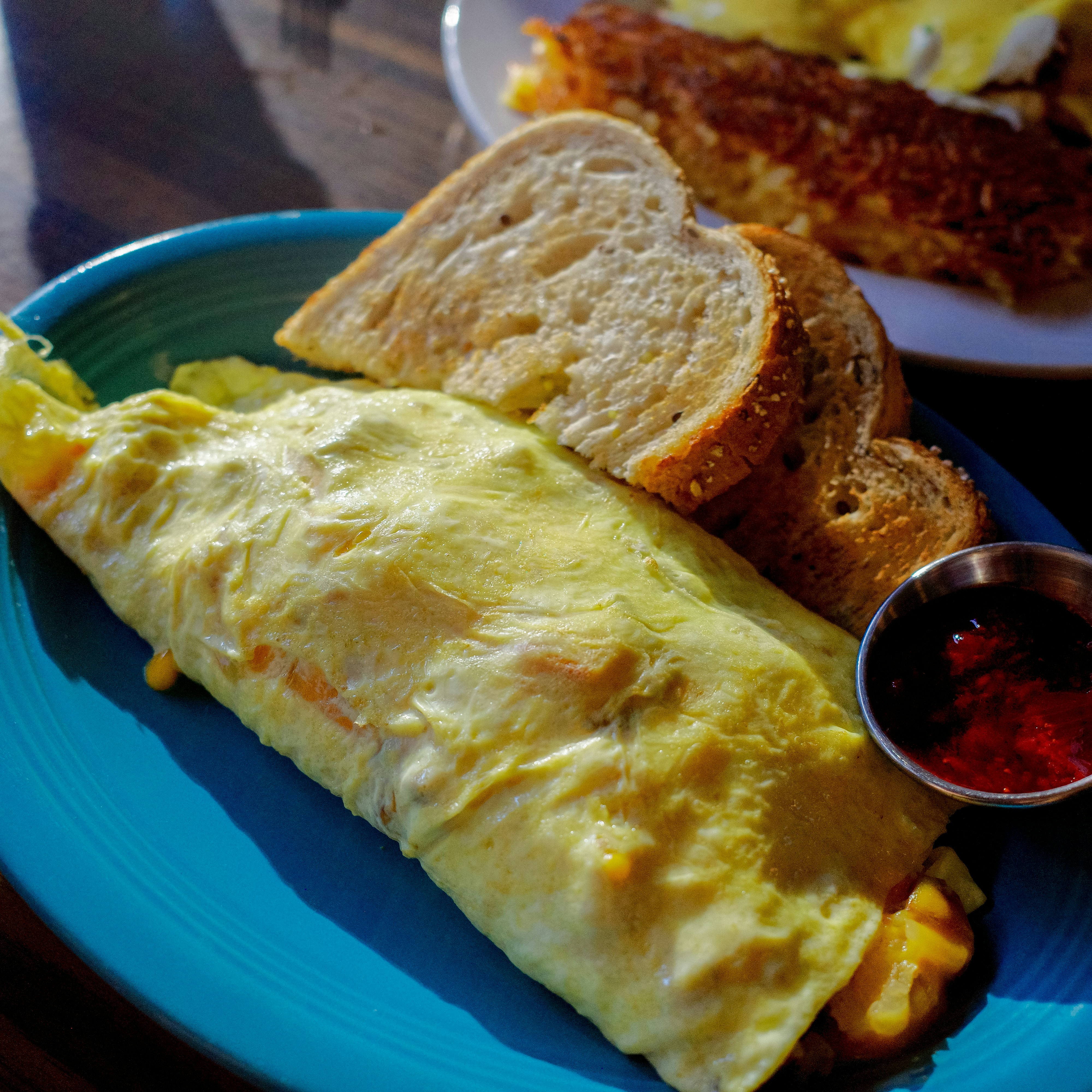 Egg-Wrapped Sunrise: Omelet on a Blue Plate with Toast