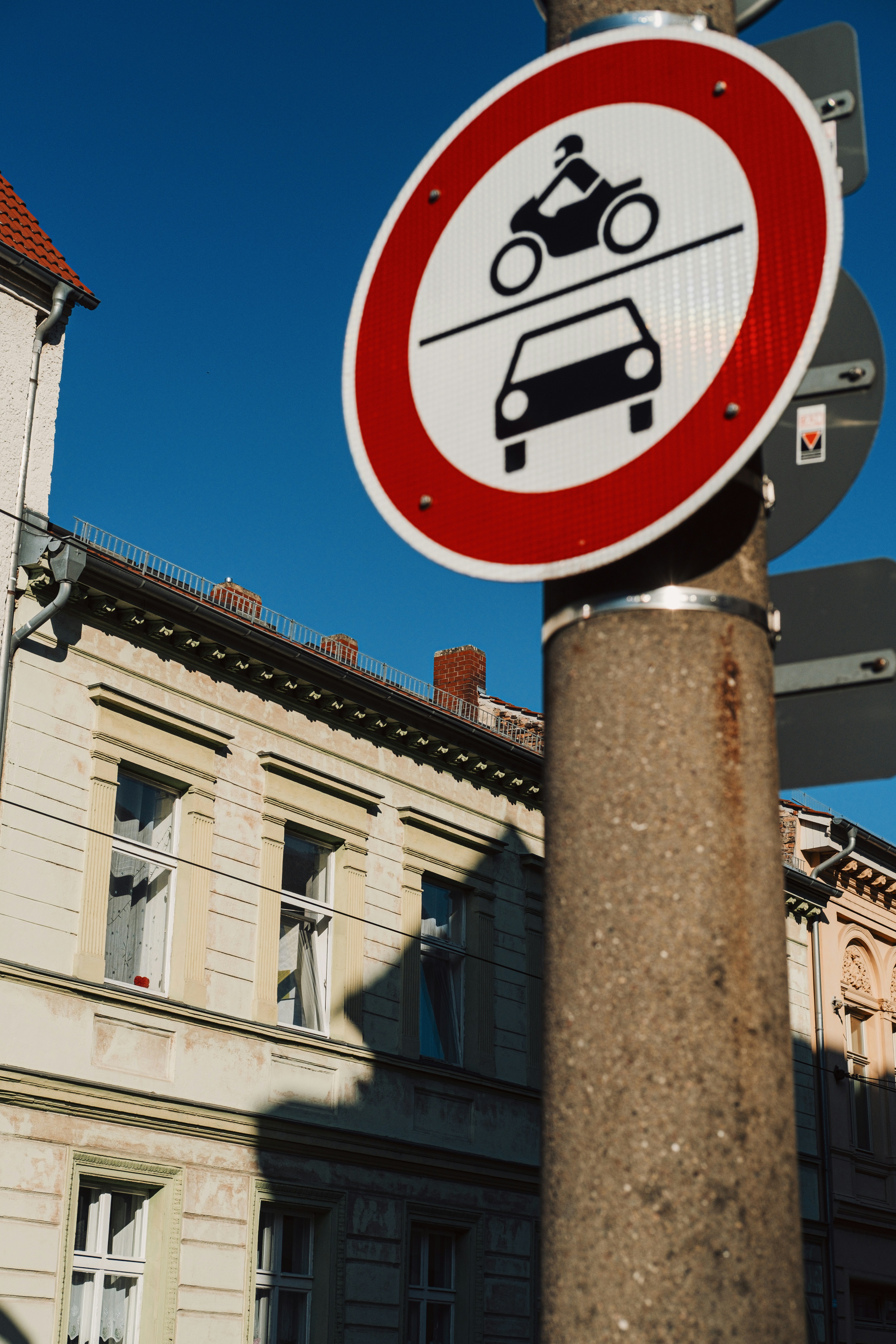 Motorcycle and Car Restriction Sign Dominates a Sunlit European Street