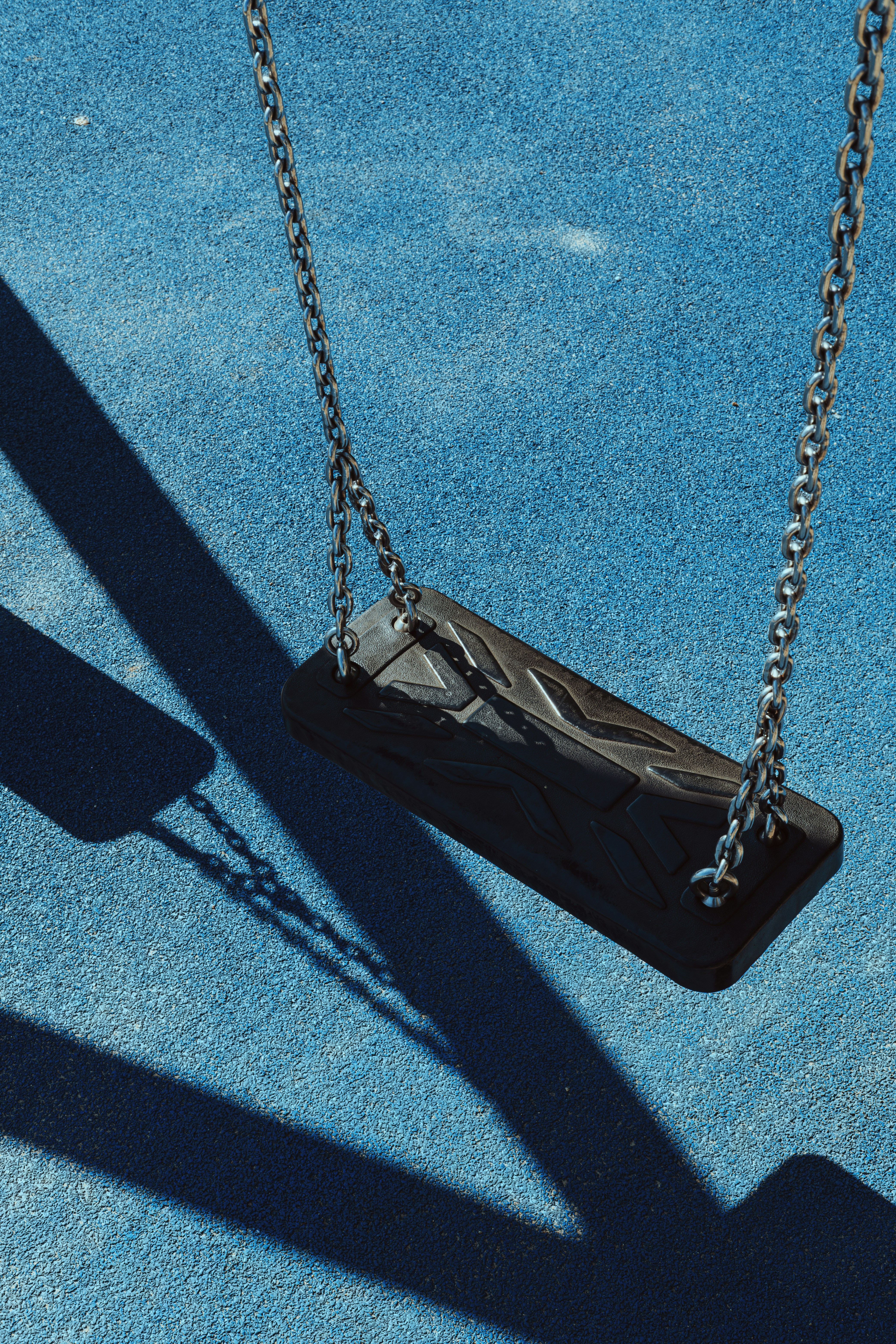 Blue Playground Swing in Strong Shadow Lines