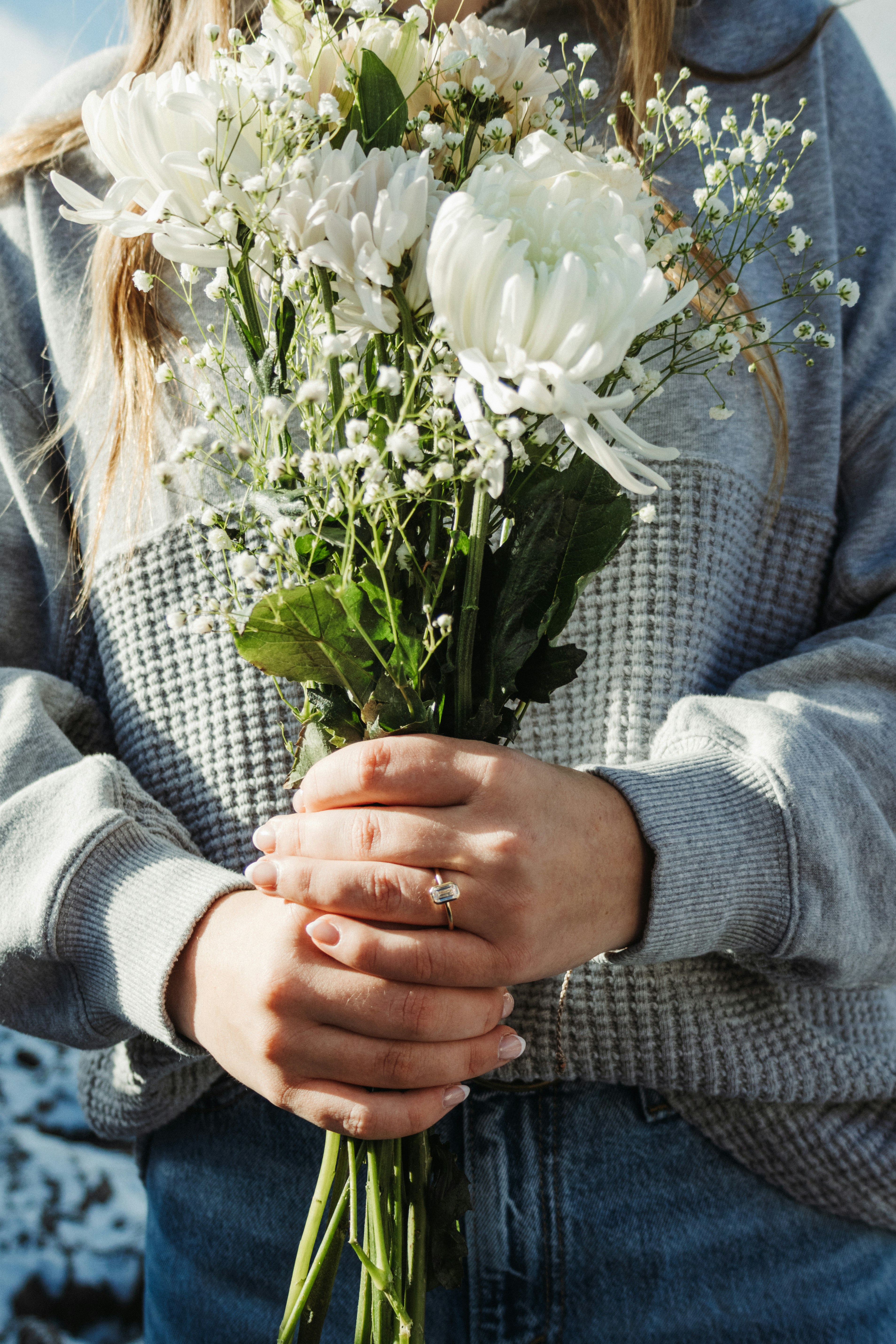 Whitened blooms and gentle hands: a bouquet held close
