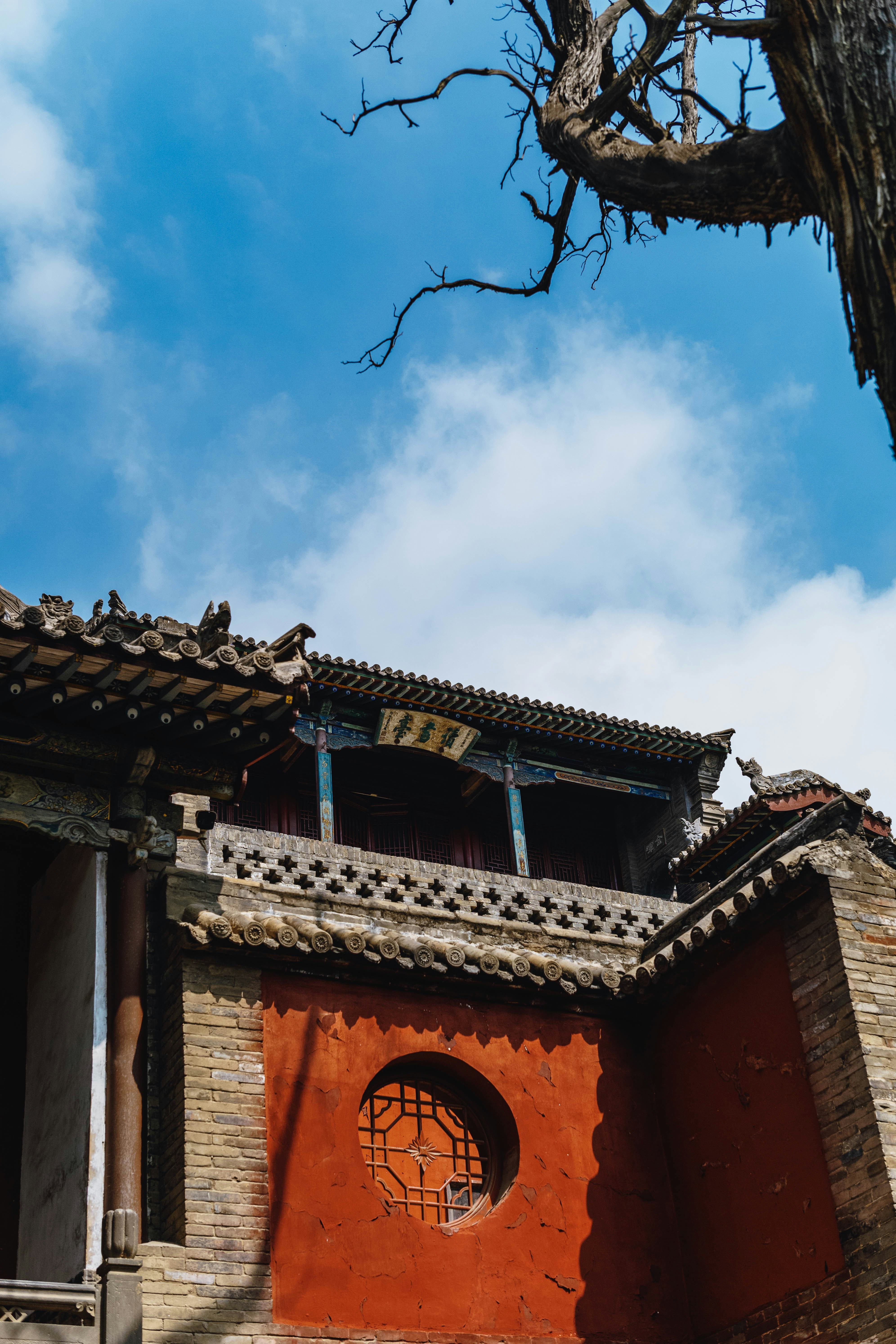 Red Circular Window and Lintel: A Corner of Ancient Chinese Architecture Against a Bright Sky