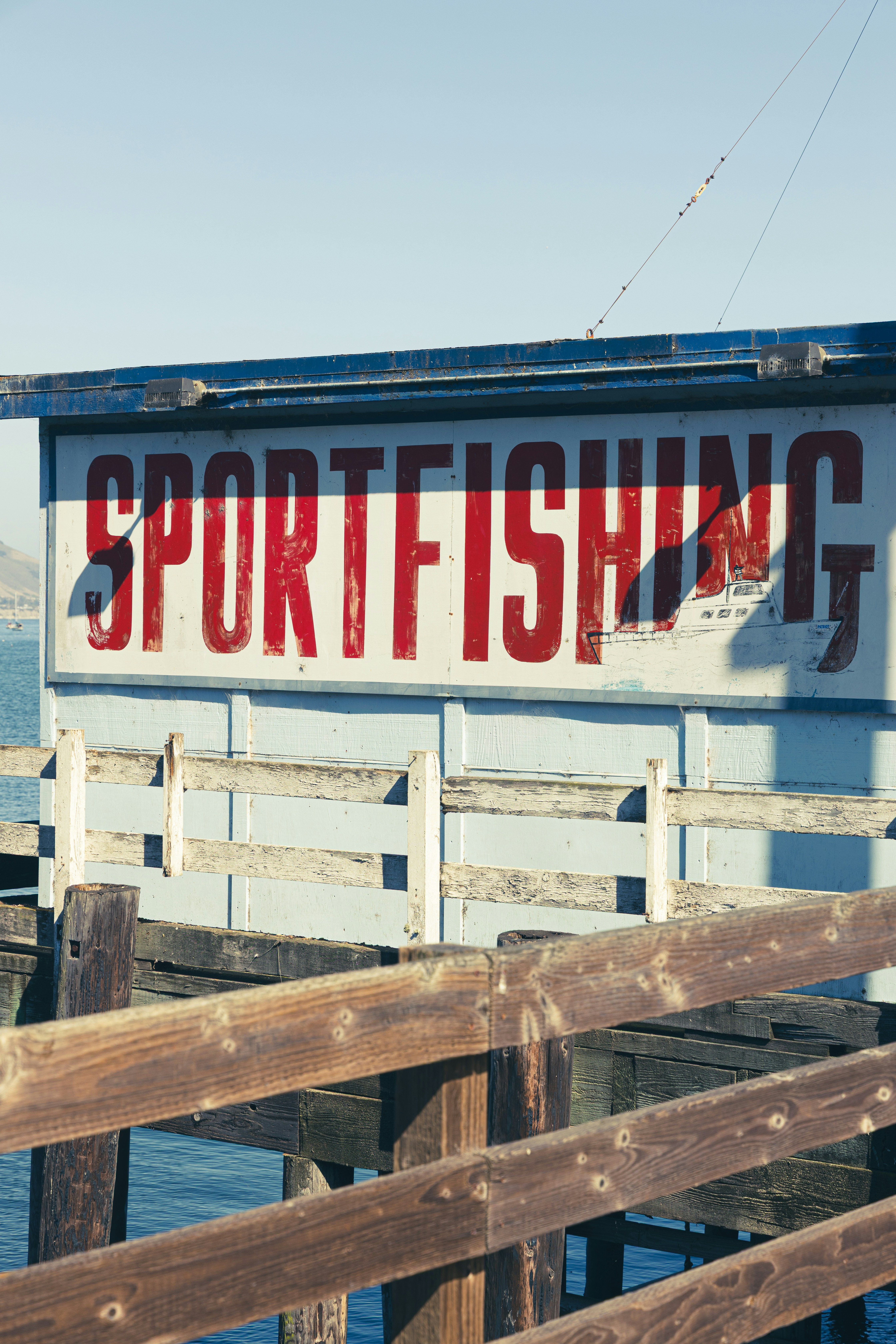 Sporting Sign on the Pier: A Weathered Welcome by the Water