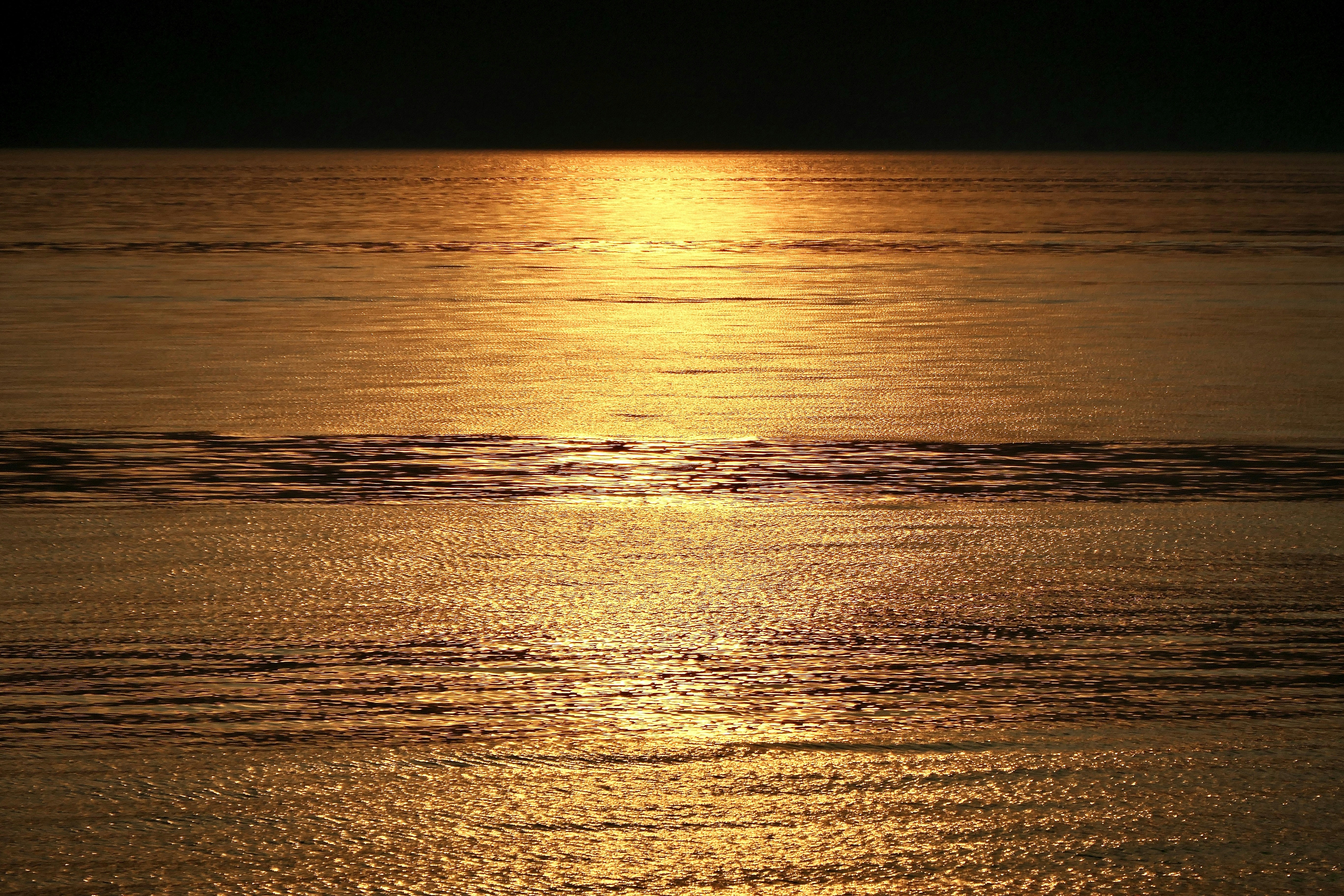 Golden Horizon: A Quiet Sea Reflects a Sunset’s Glow