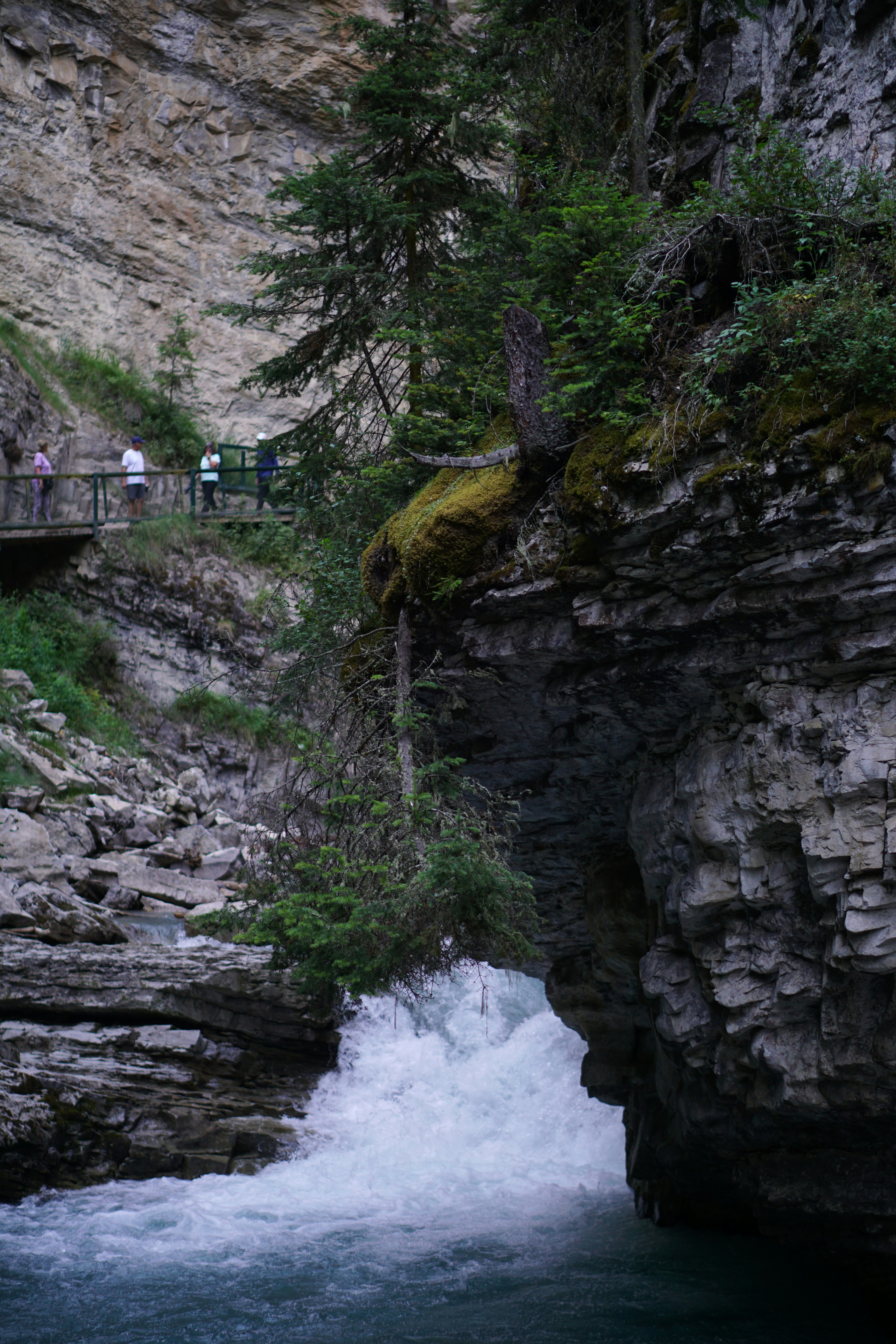 Rugged Gorge Walkway: People Crossing a Narrow Cliffside Bridge