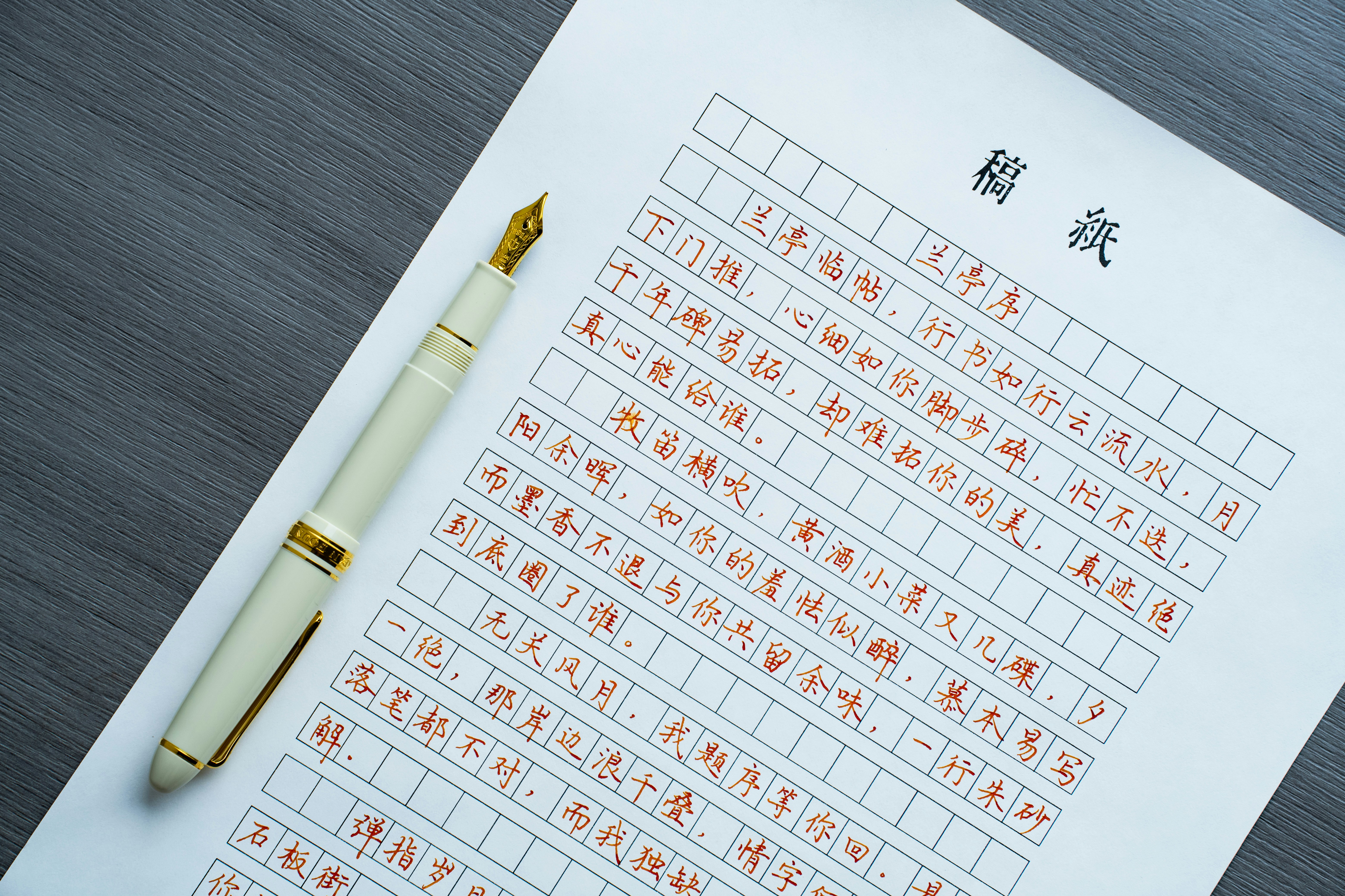 Calligraphy in Focus: A Fountain Pen Beside a Manuscript Grid