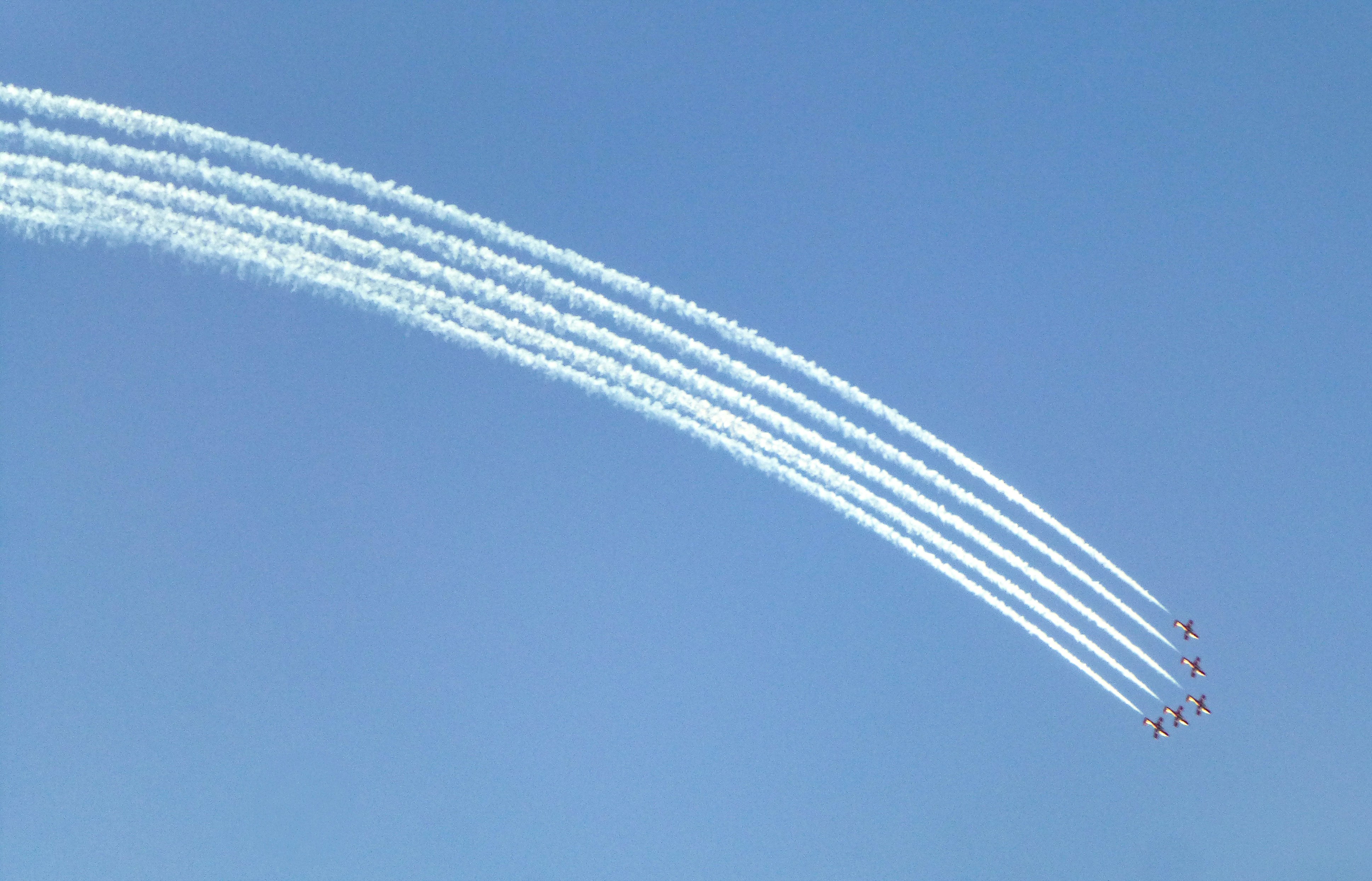 Aviation Arc: four-jet contrails carving across a clear blue sky