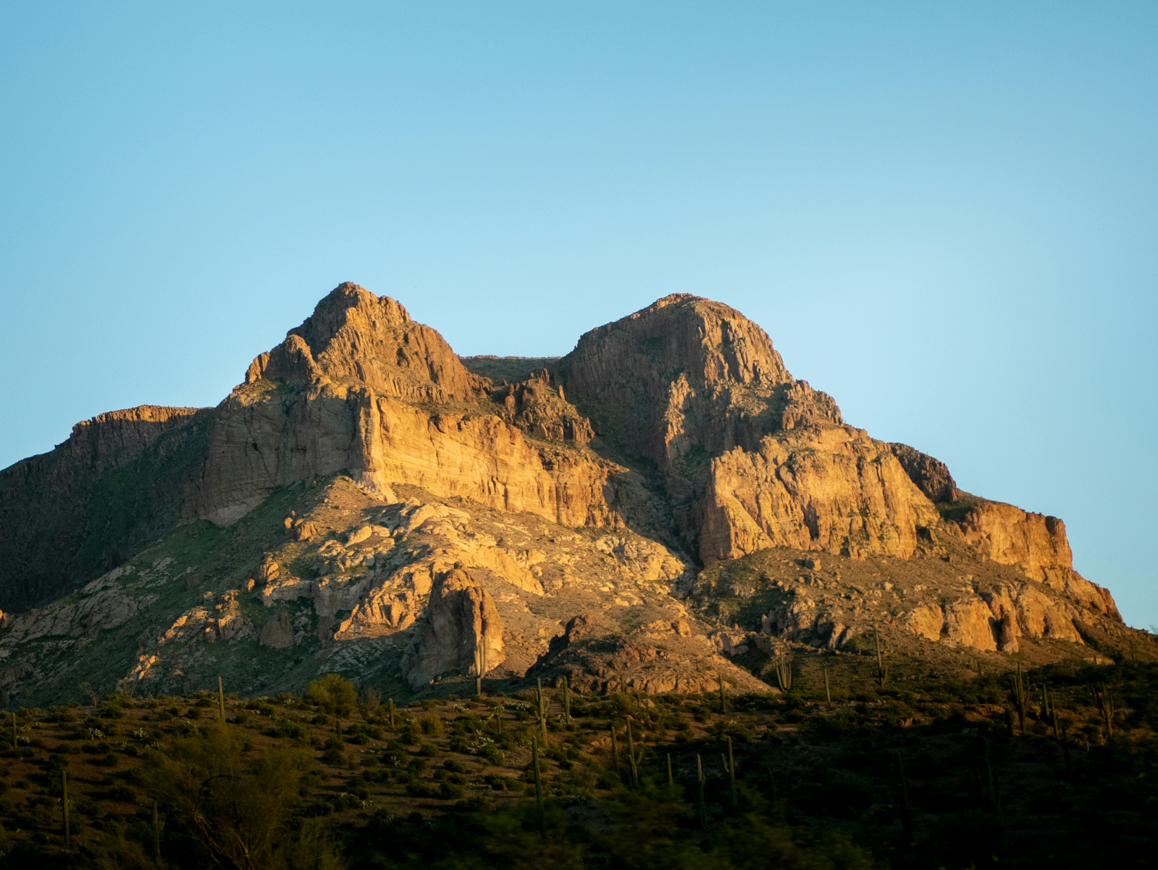 Golden Summit: Sunlit Peak Against a Clear Desert Sky