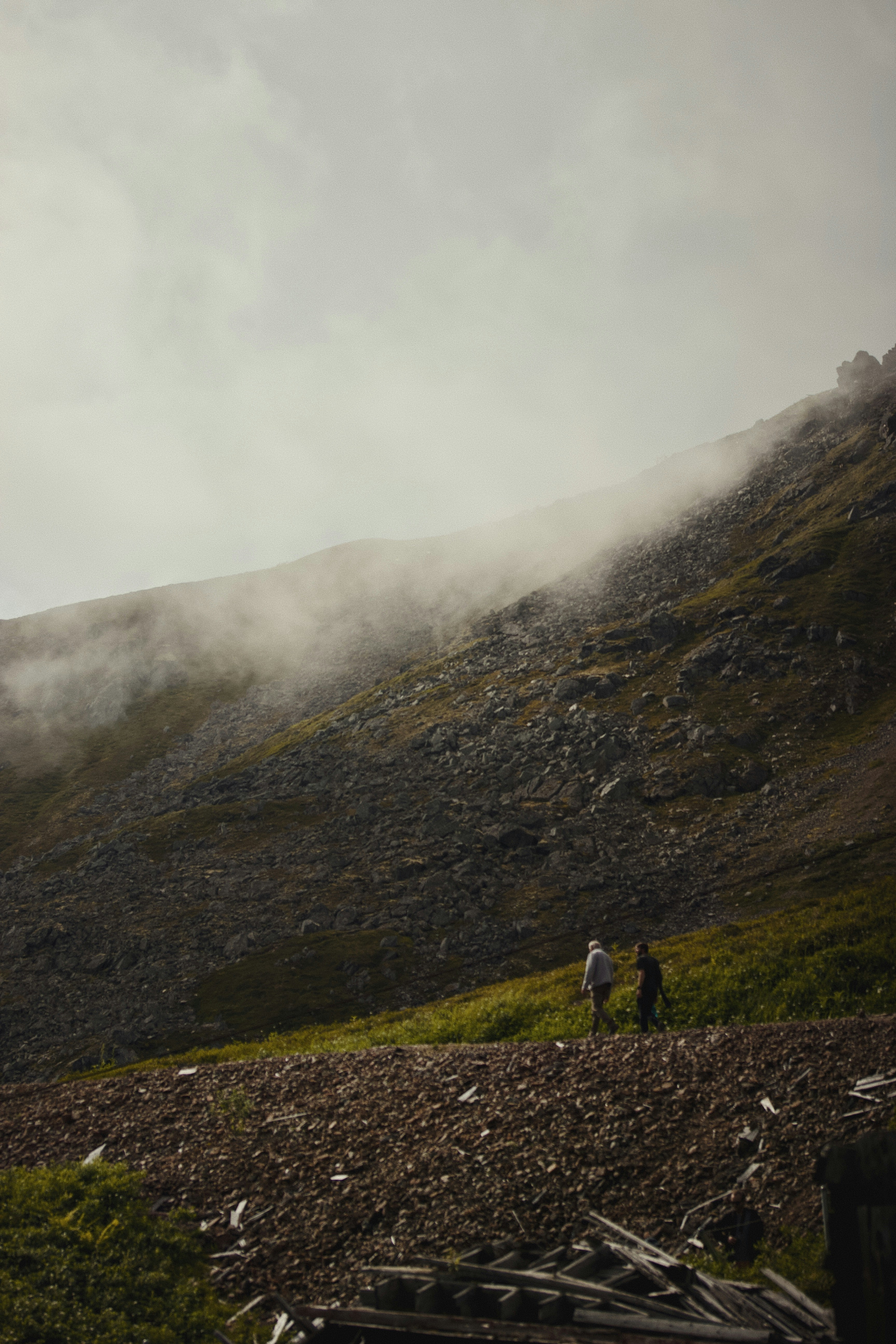 Hikers On a Rocky Slope Beneath Misty Peaks