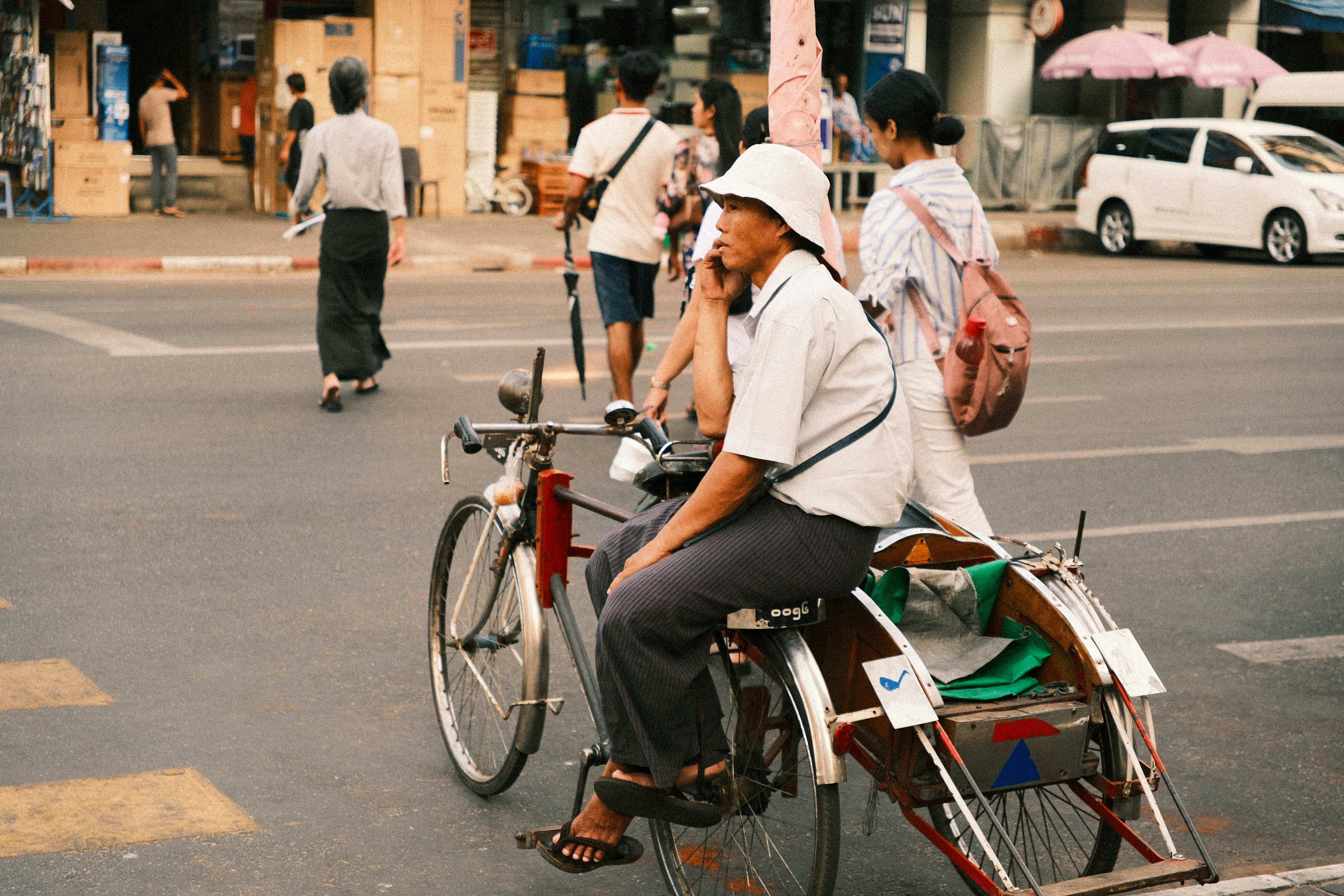 Tailwind of City Life: A Cyclist Pauses by the Crosswalk
