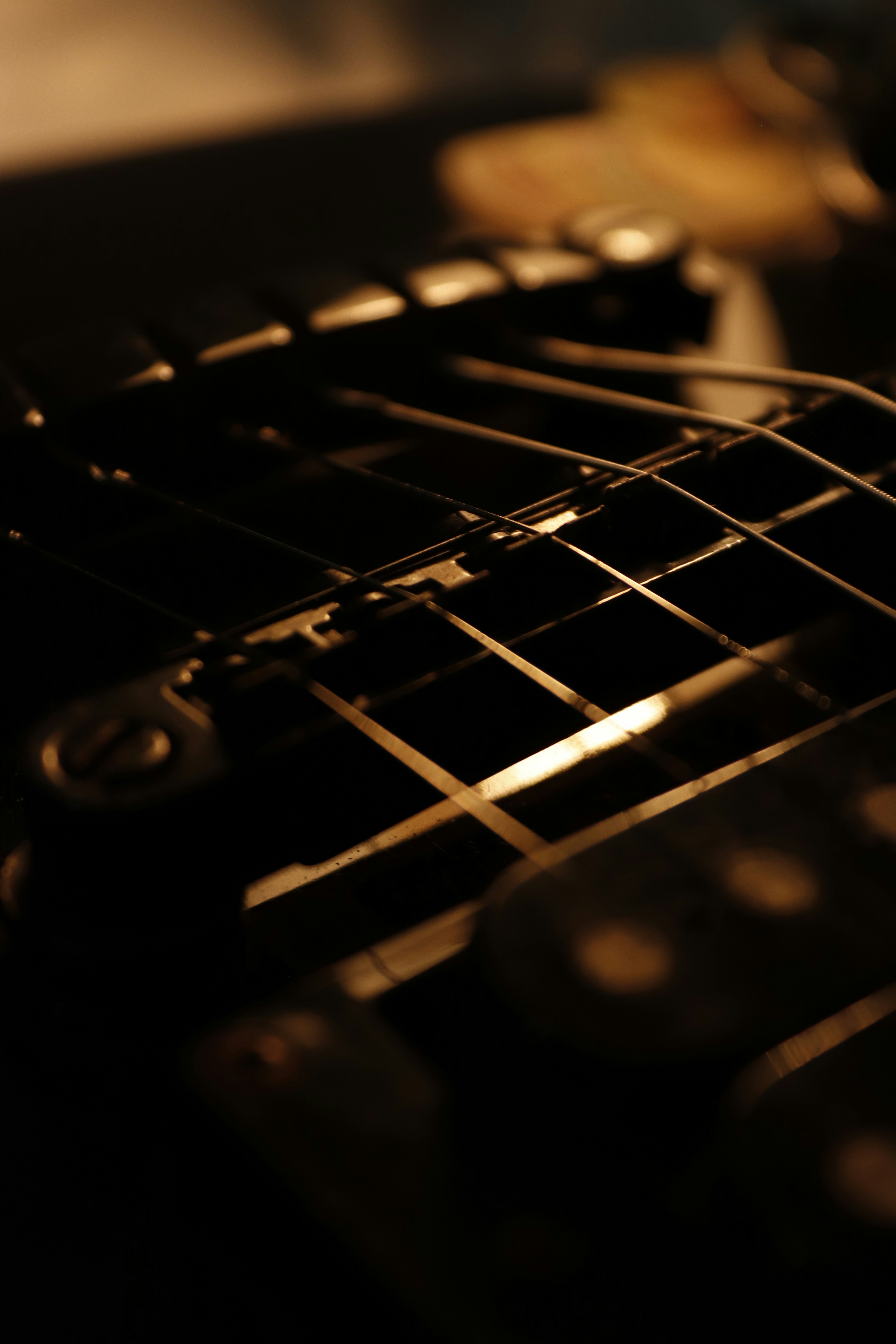 Strings in Shadow: Close-up of Guitar Bridge Under Warm Glow