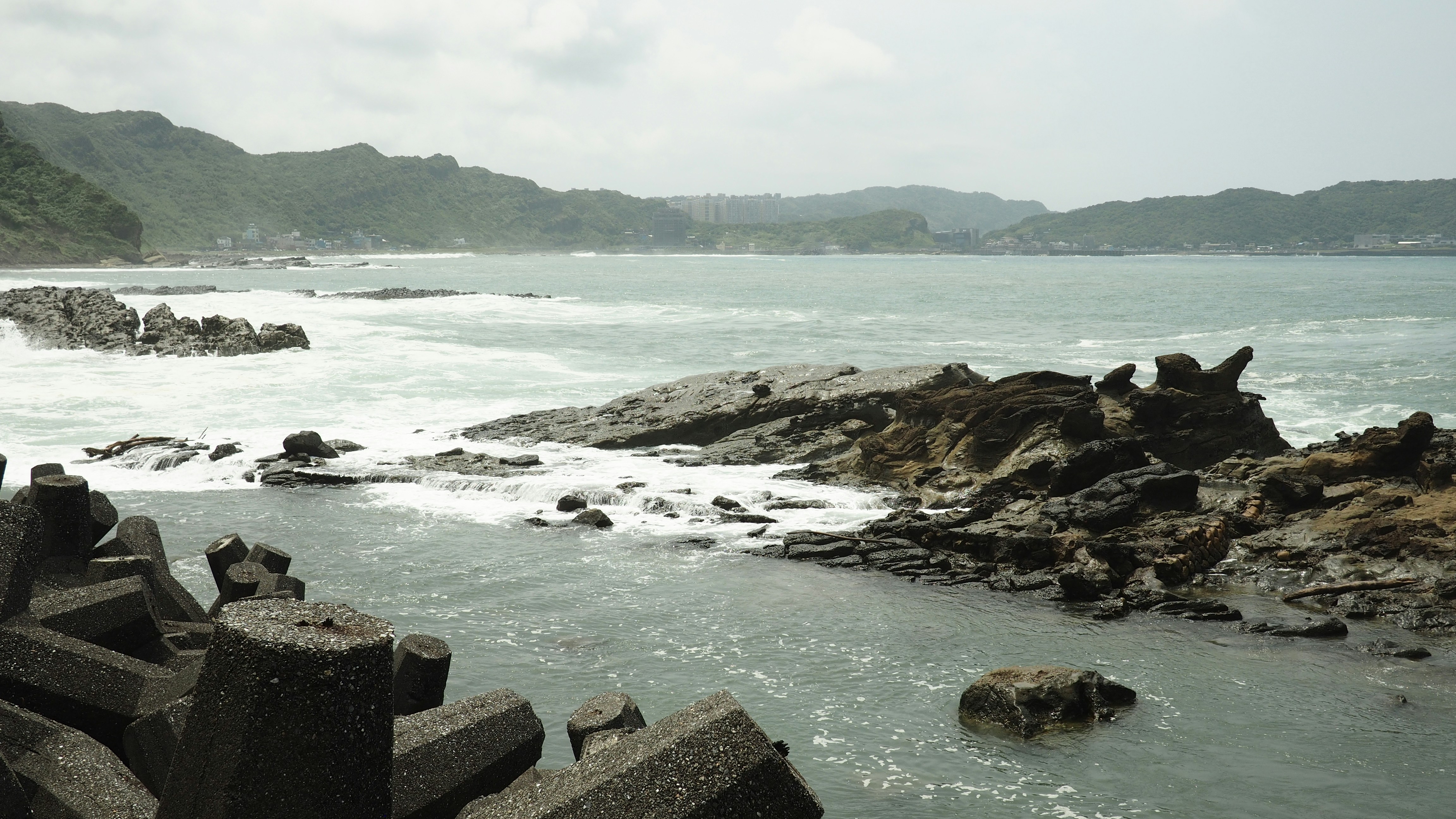 Rugged shoreline under a calm sky with volcanic rock formations