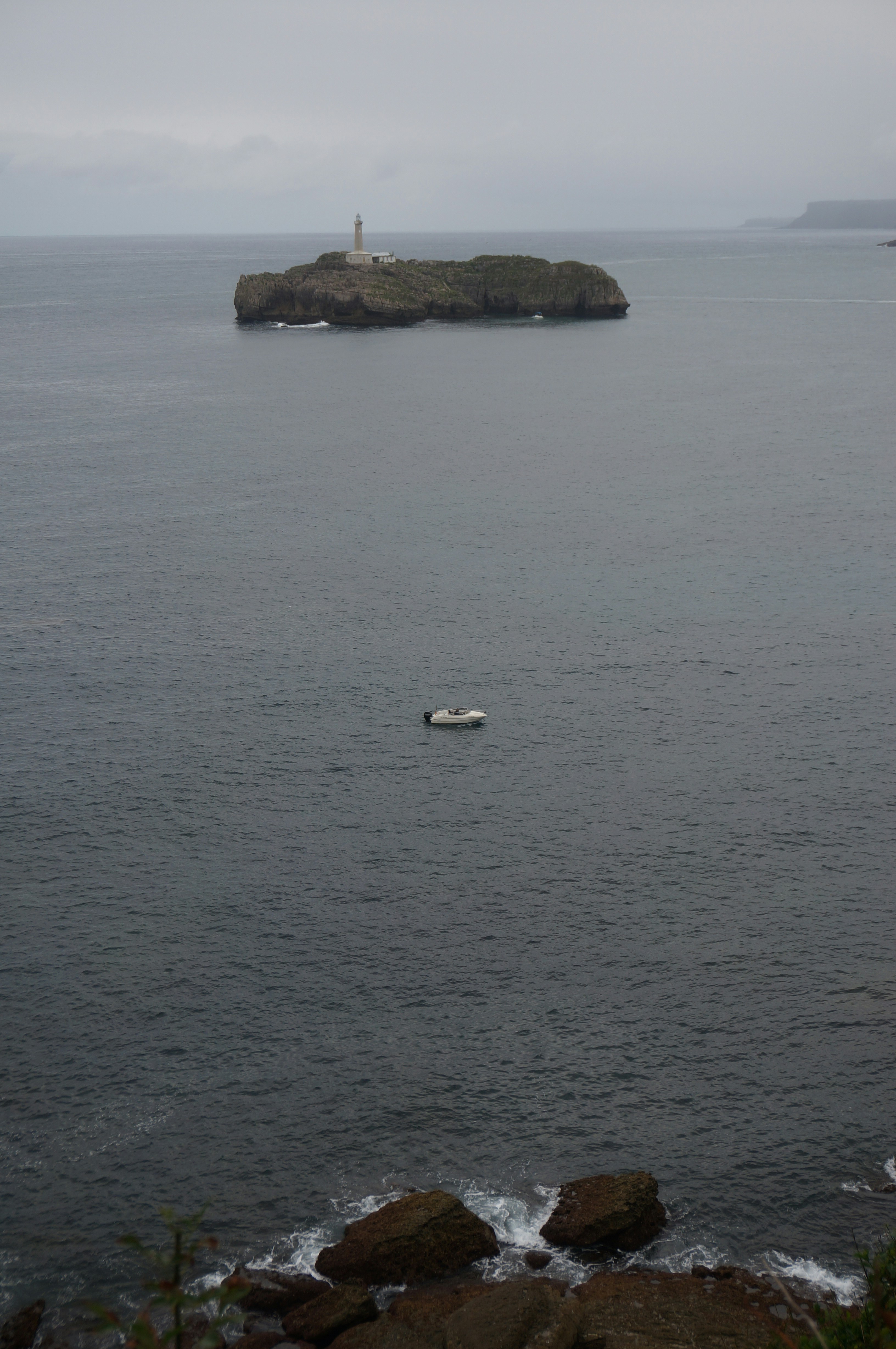 Tiny Boat, Majestic Rock: A Seascape's Quiet Sentinel