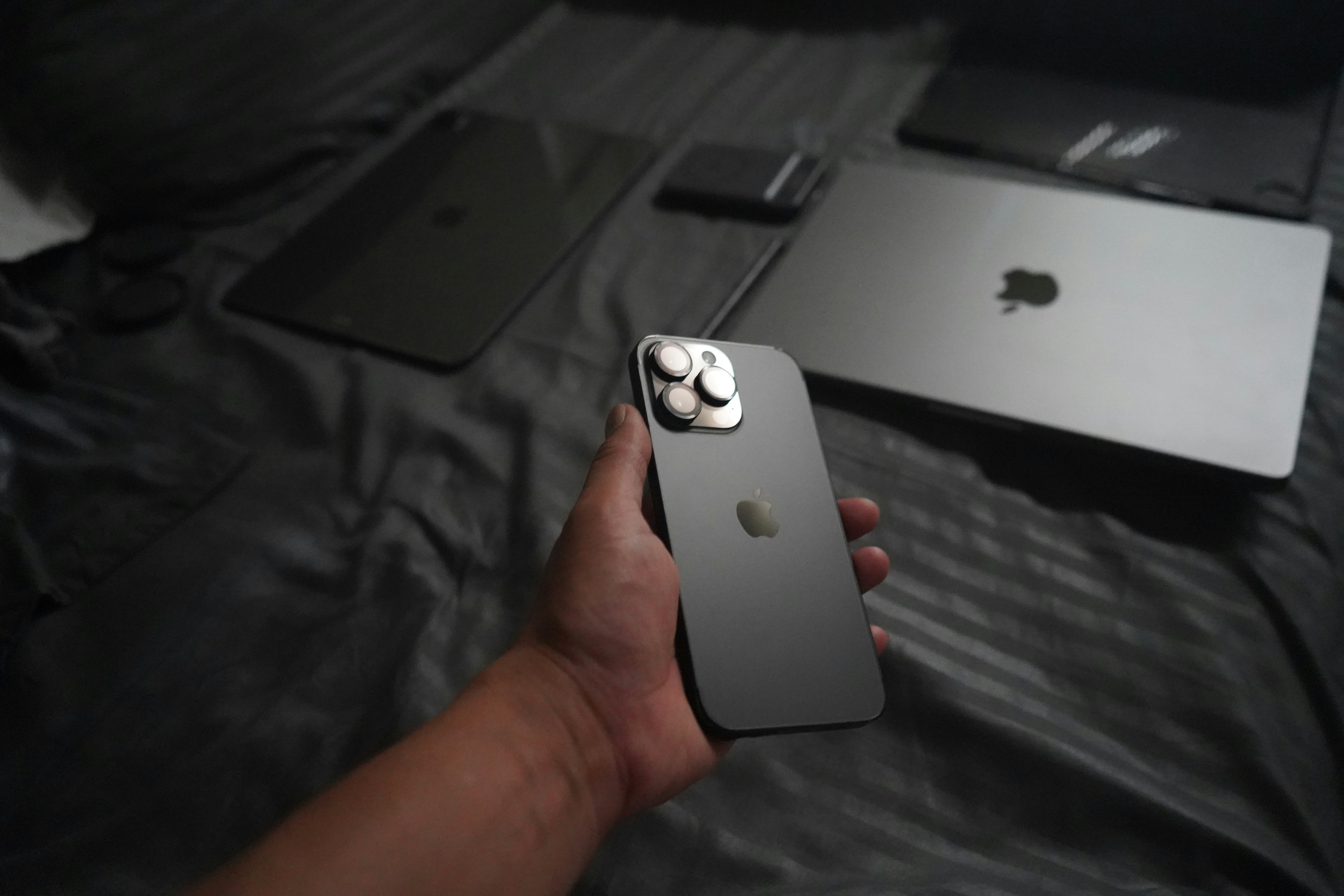 In-Hand iPhone 15 Pro atop a Workspace of Tech