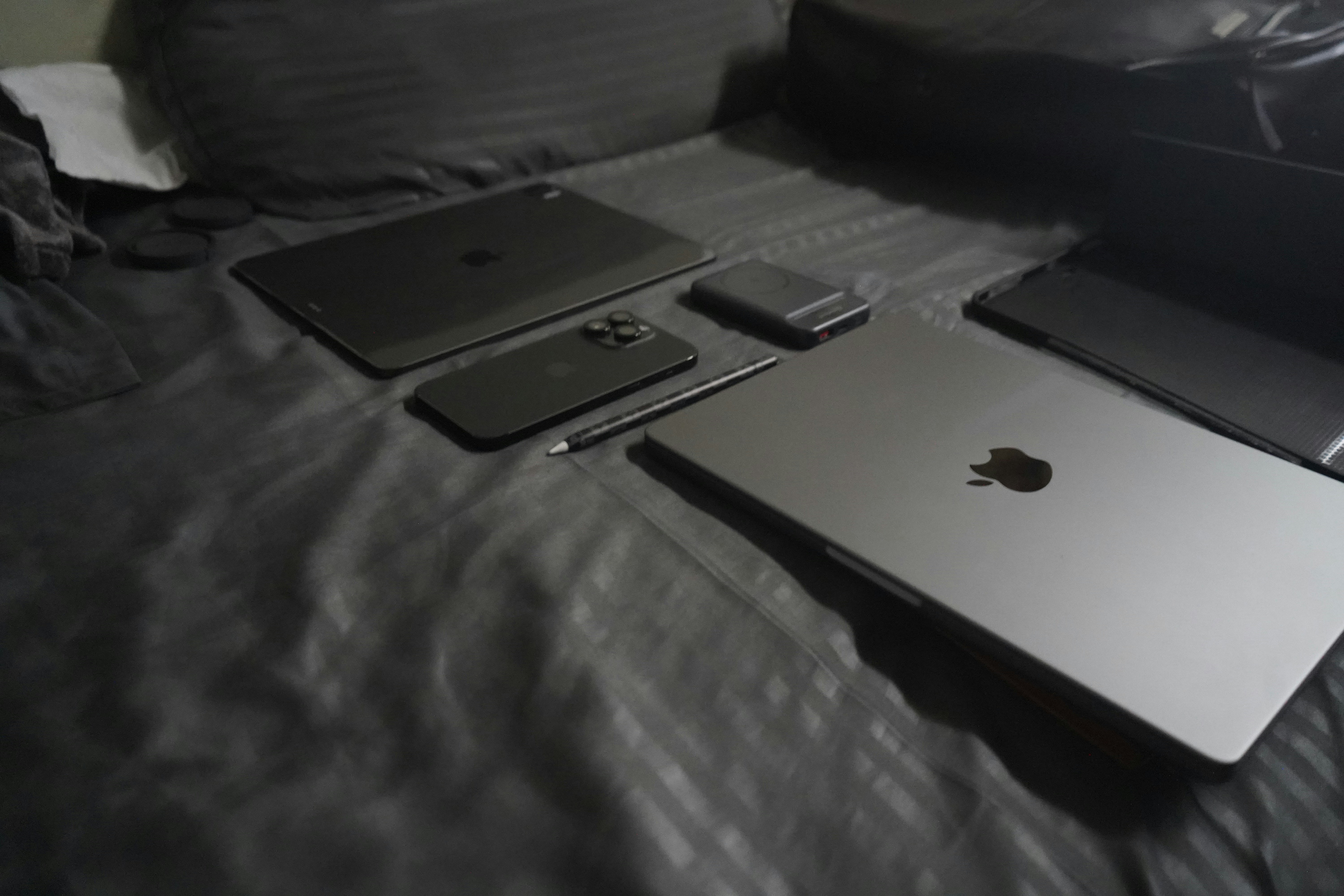 Workspace in Focus: Apple devices and a lone stylus resting on a rumpled bedspread