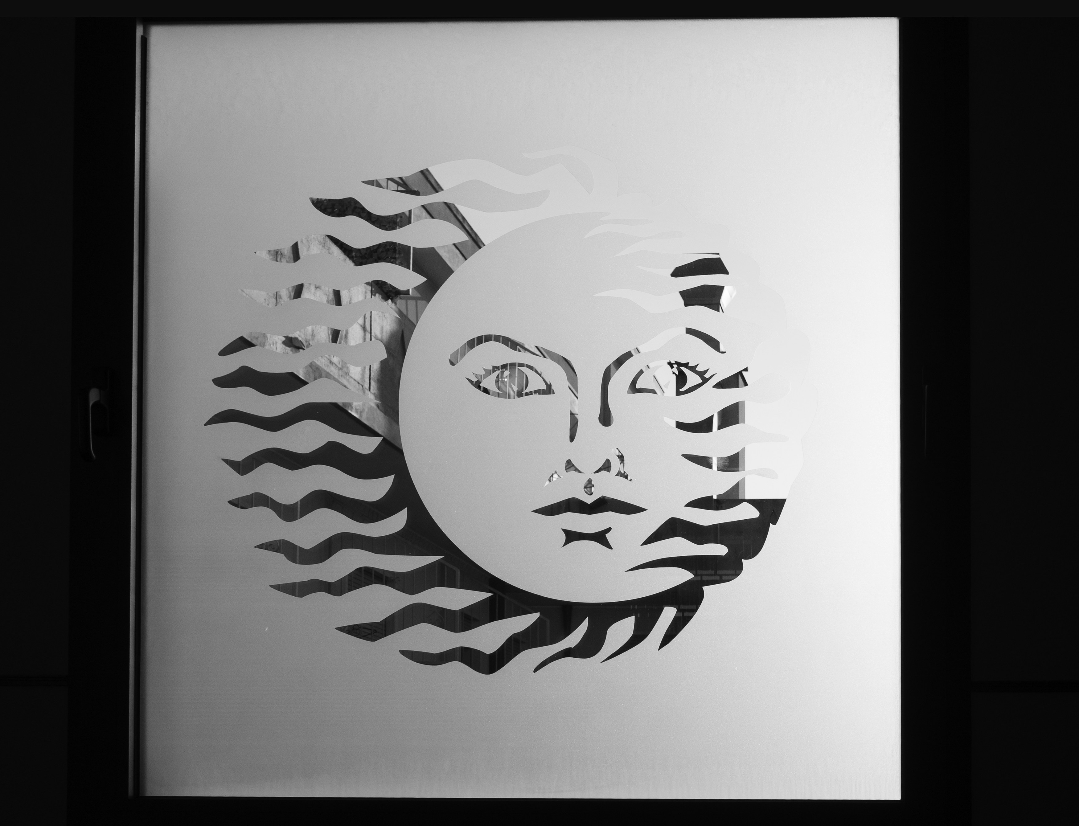 Moonlit Cutout: A Circular Sun Face in Glass