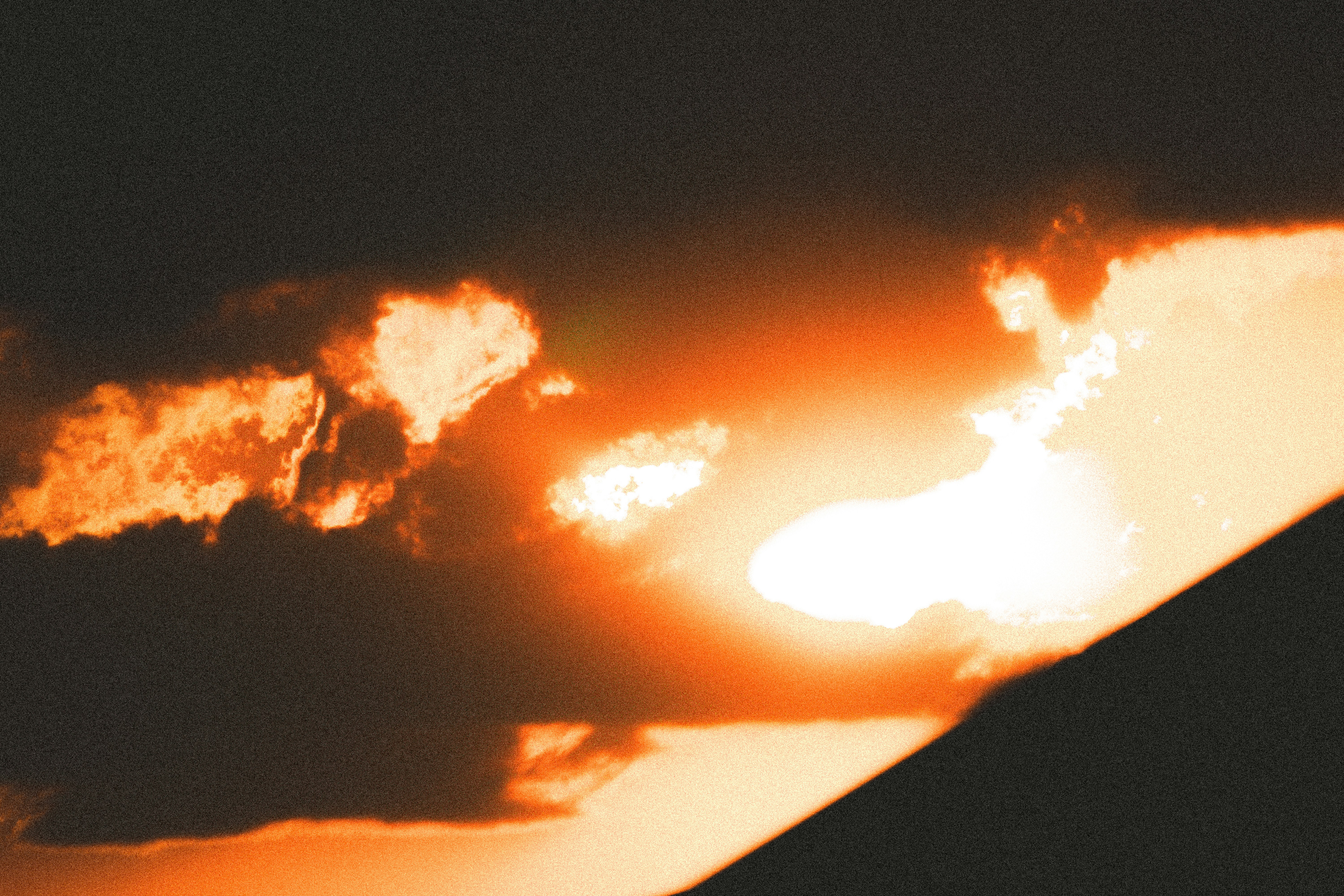 Crimson Horizon: Sunlit Clouds Veil a Sloping Rooftop