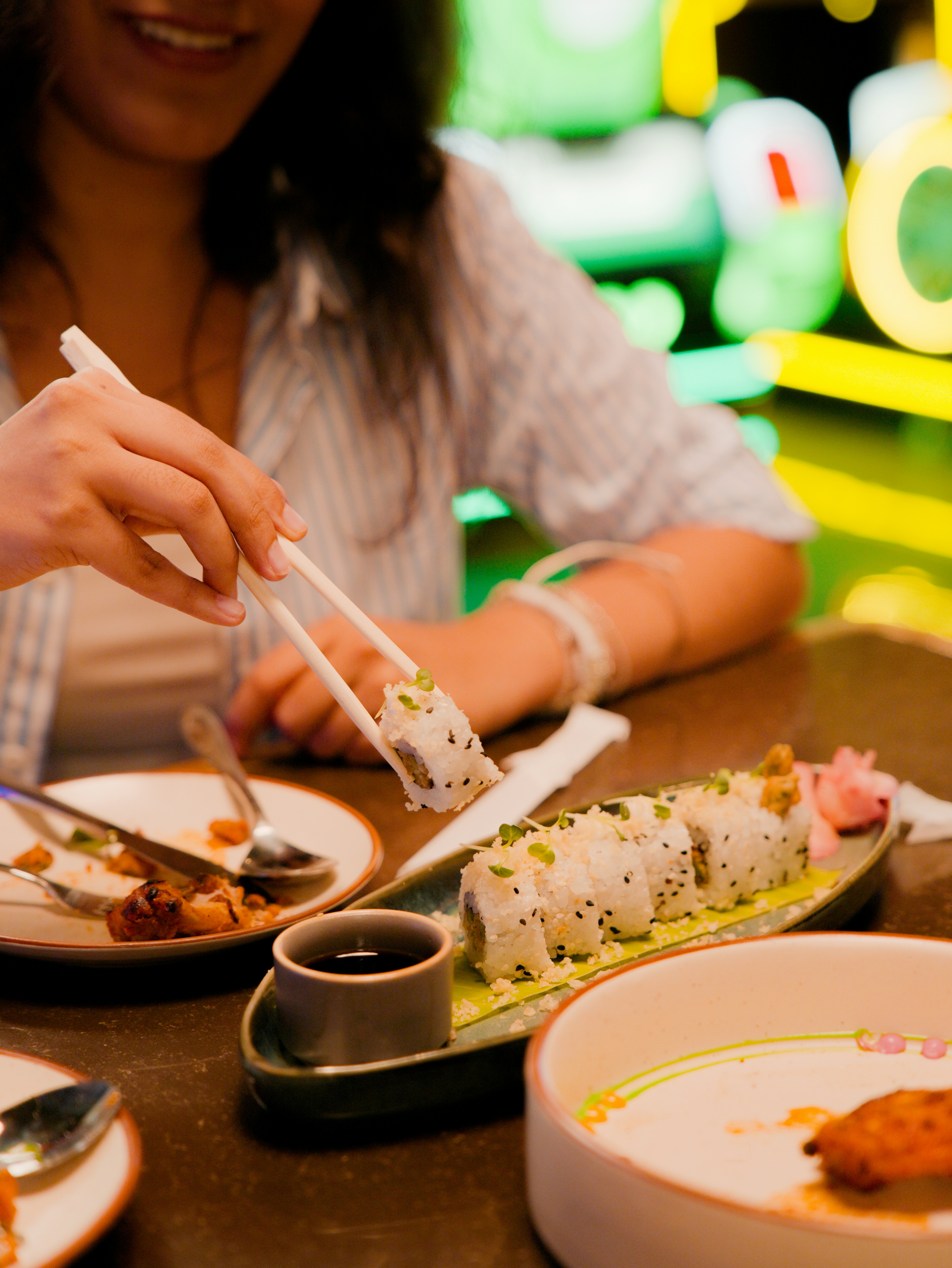 Chopsticks poised over a sushi plate: a casual dining moment