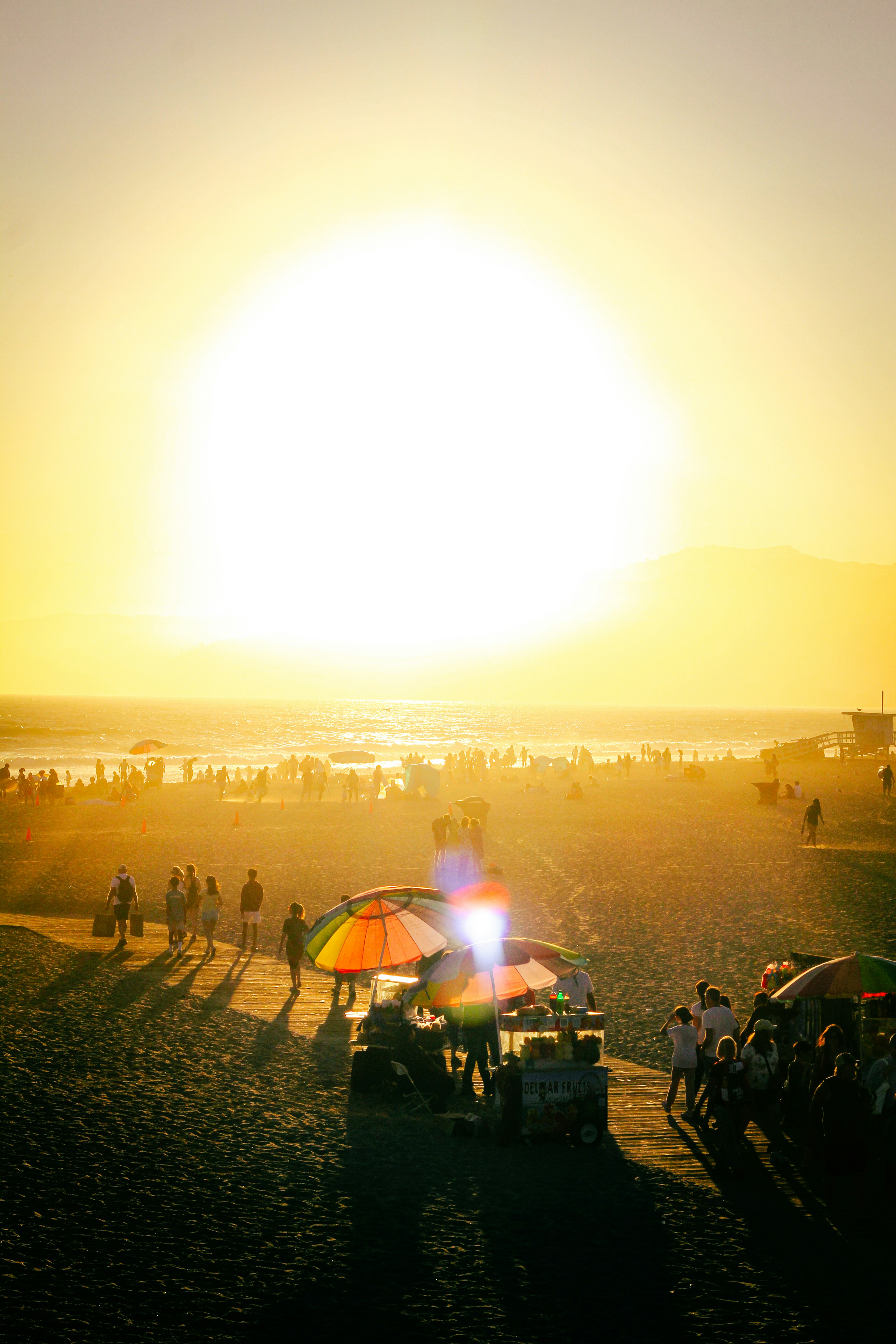 Sunlit Beach Vistas: A Crowded Shore Under a Radiant Evening