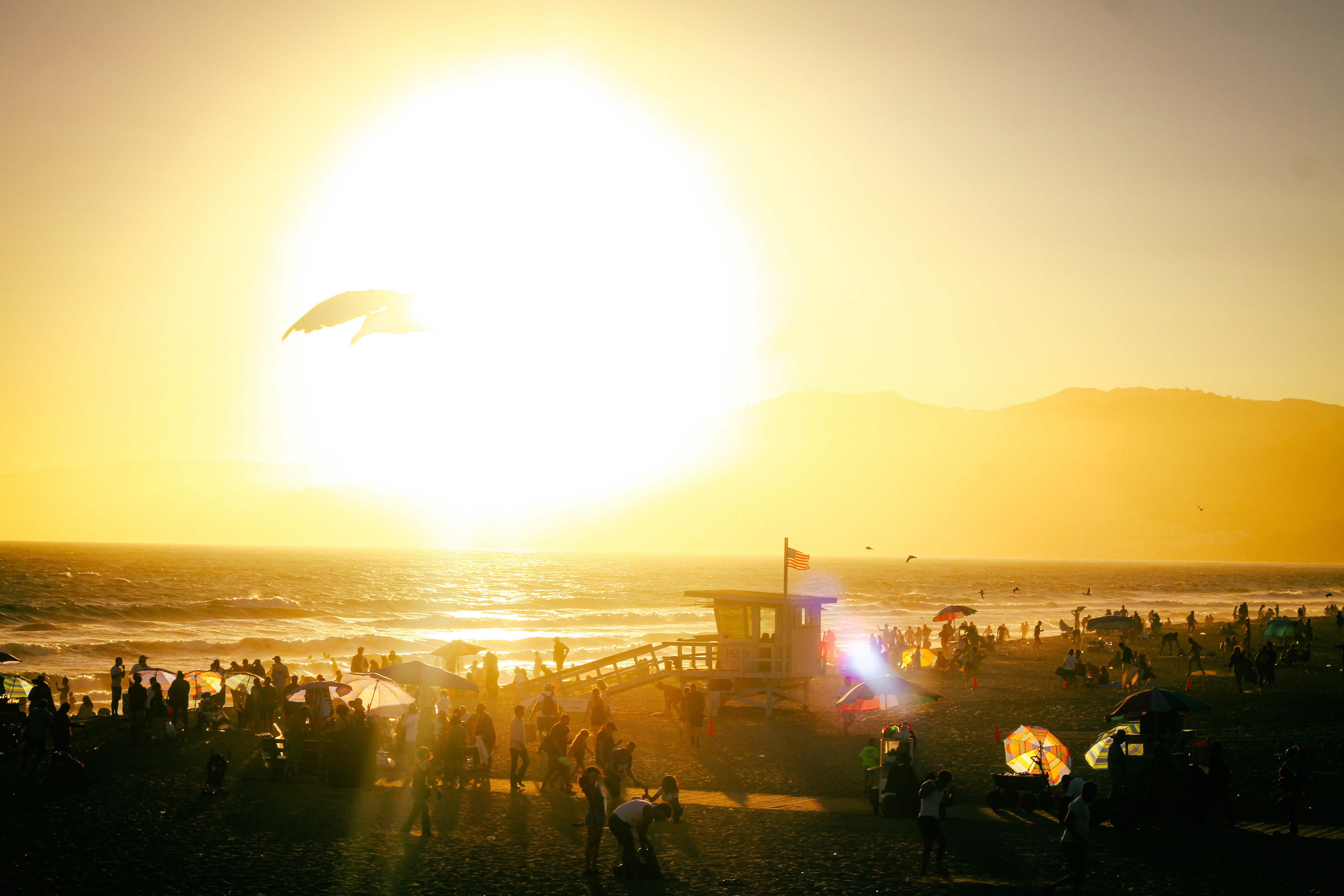 Sun at the Edge: A Crowded Beach Silhouette Beneath a Blazing Horizon