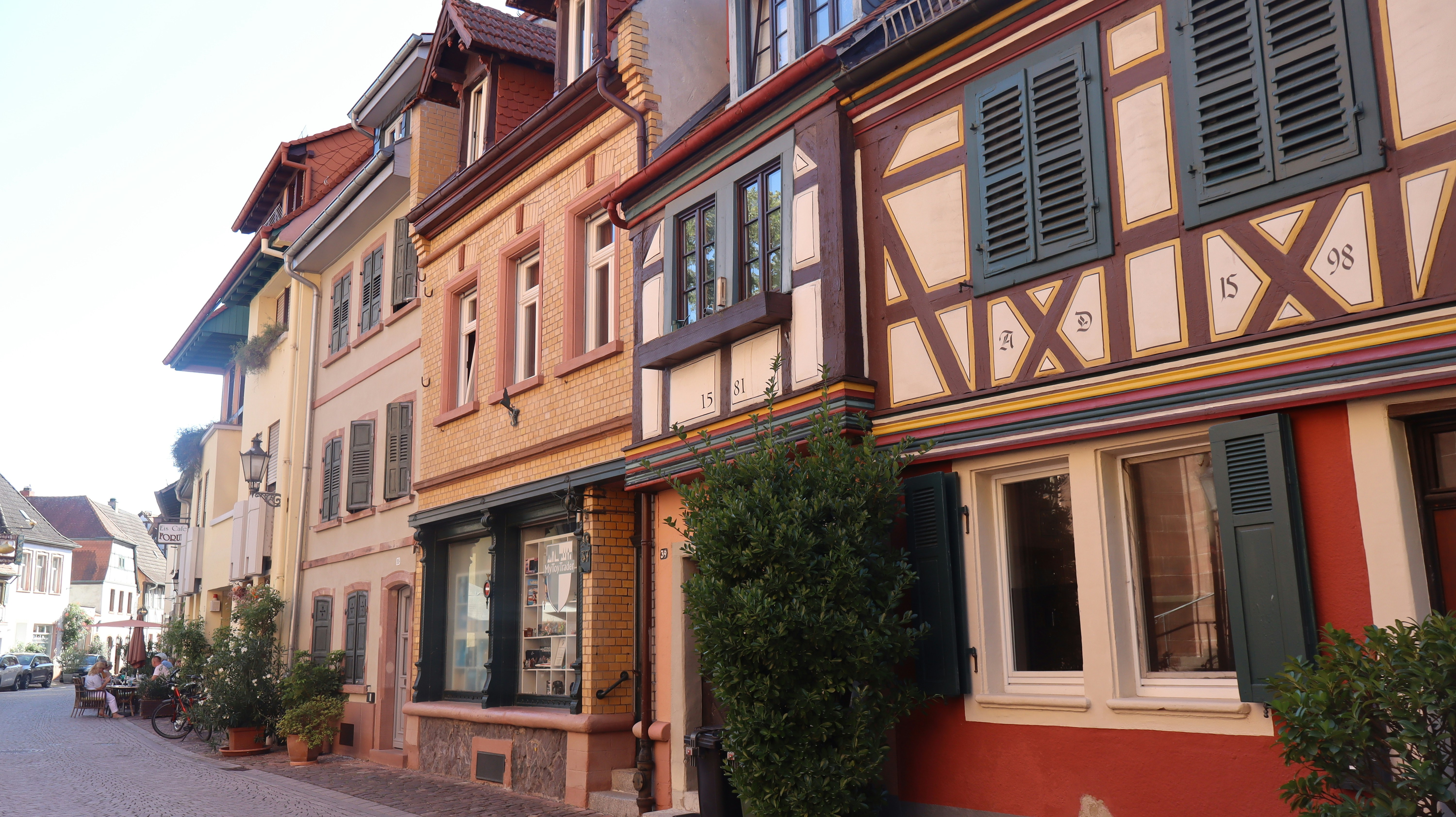 Charming row of pastel timber-framed buildings along a sunlit cobblestone street.