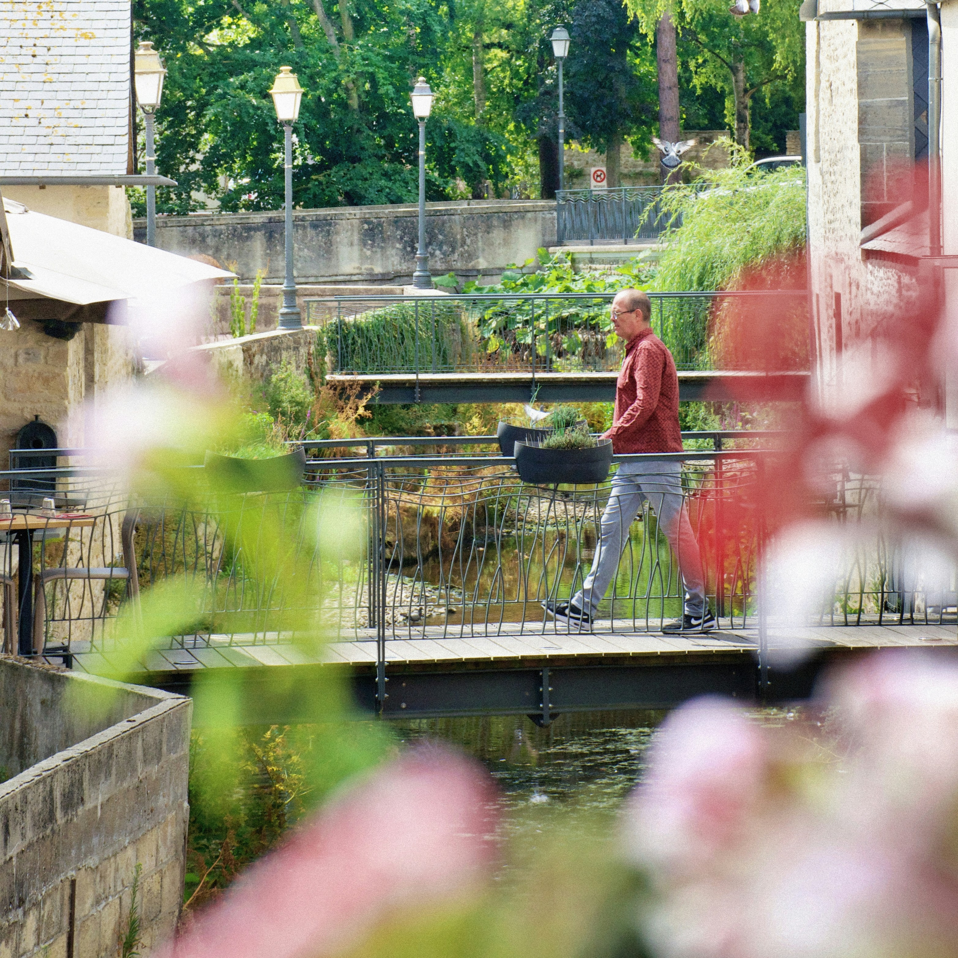 Man in rust sweater strolling a canal bridge