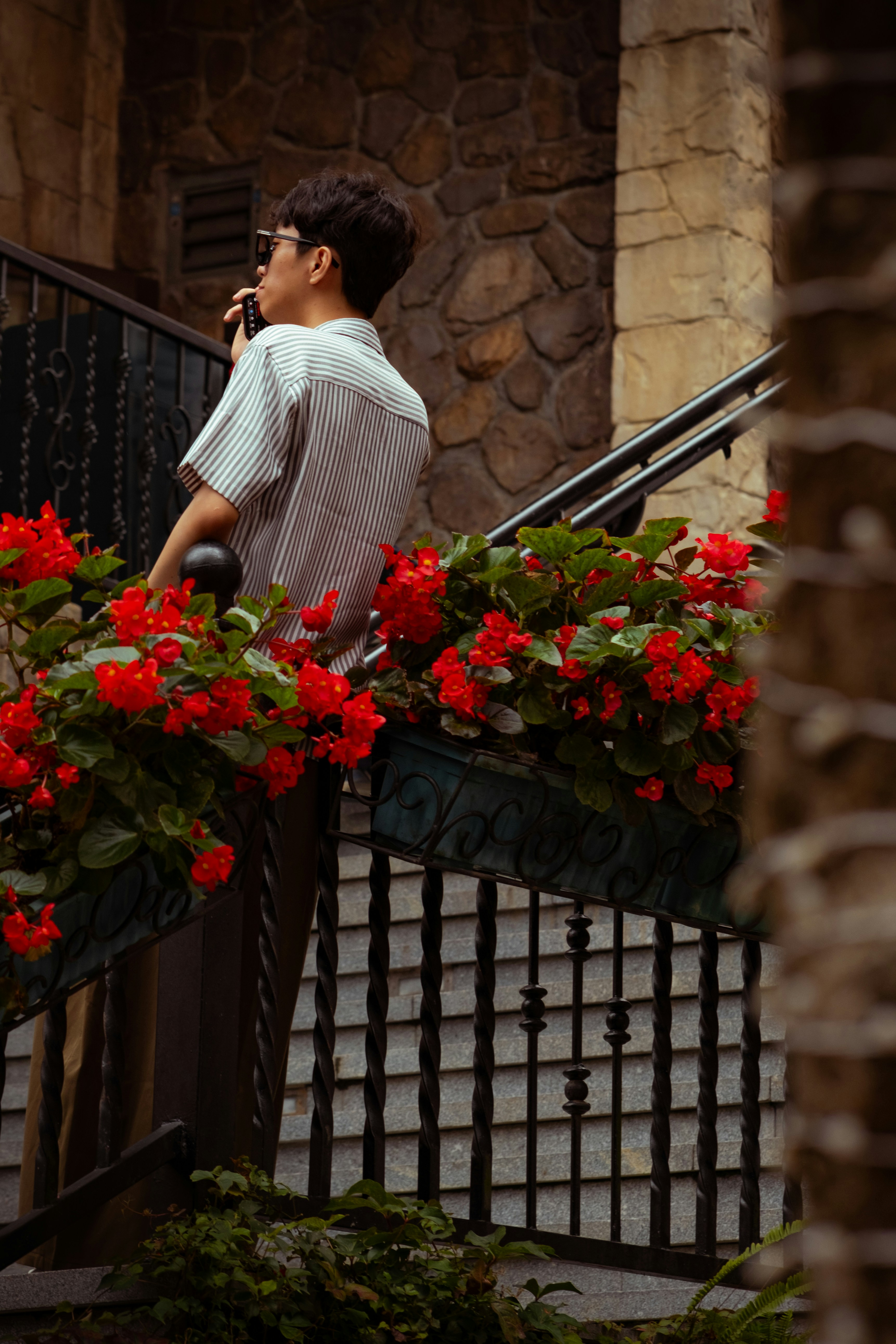 Phone-call moment on a bloom-filled balcony