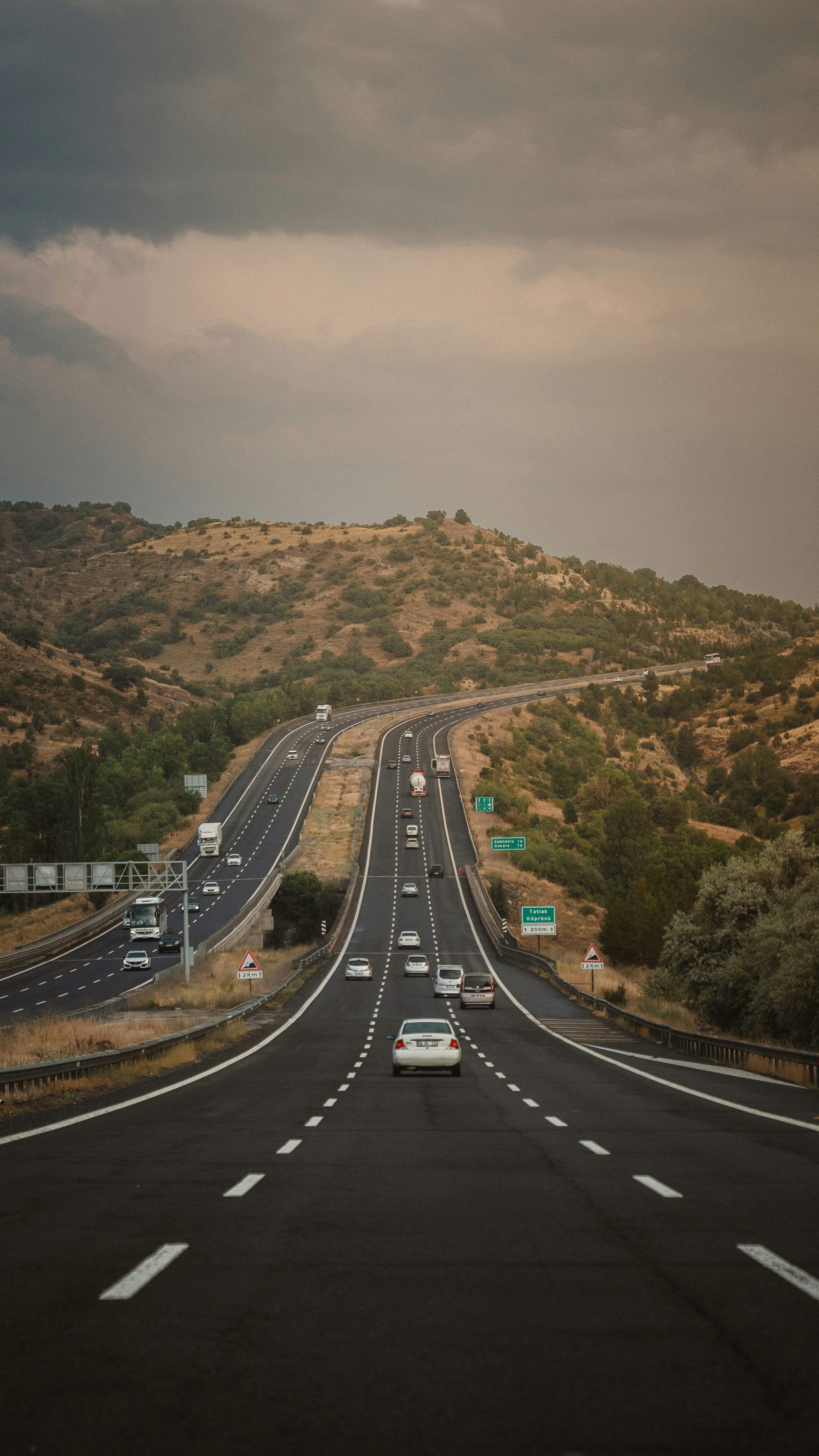 Ribbon of asphalt: a sunlit highway carving through scrubby hills