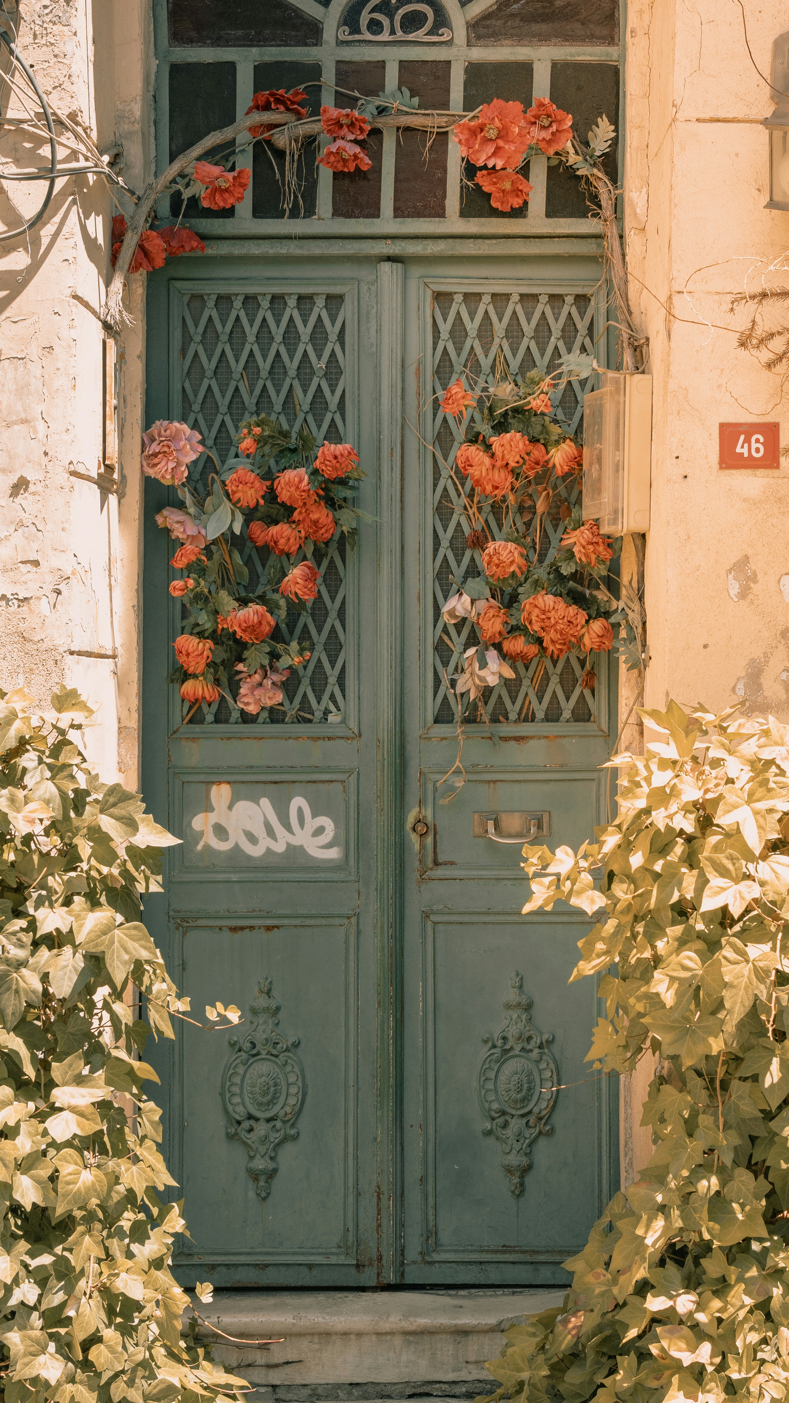 Floral Ironwork Gate: A Teal Door Framed by Roses and Ivy