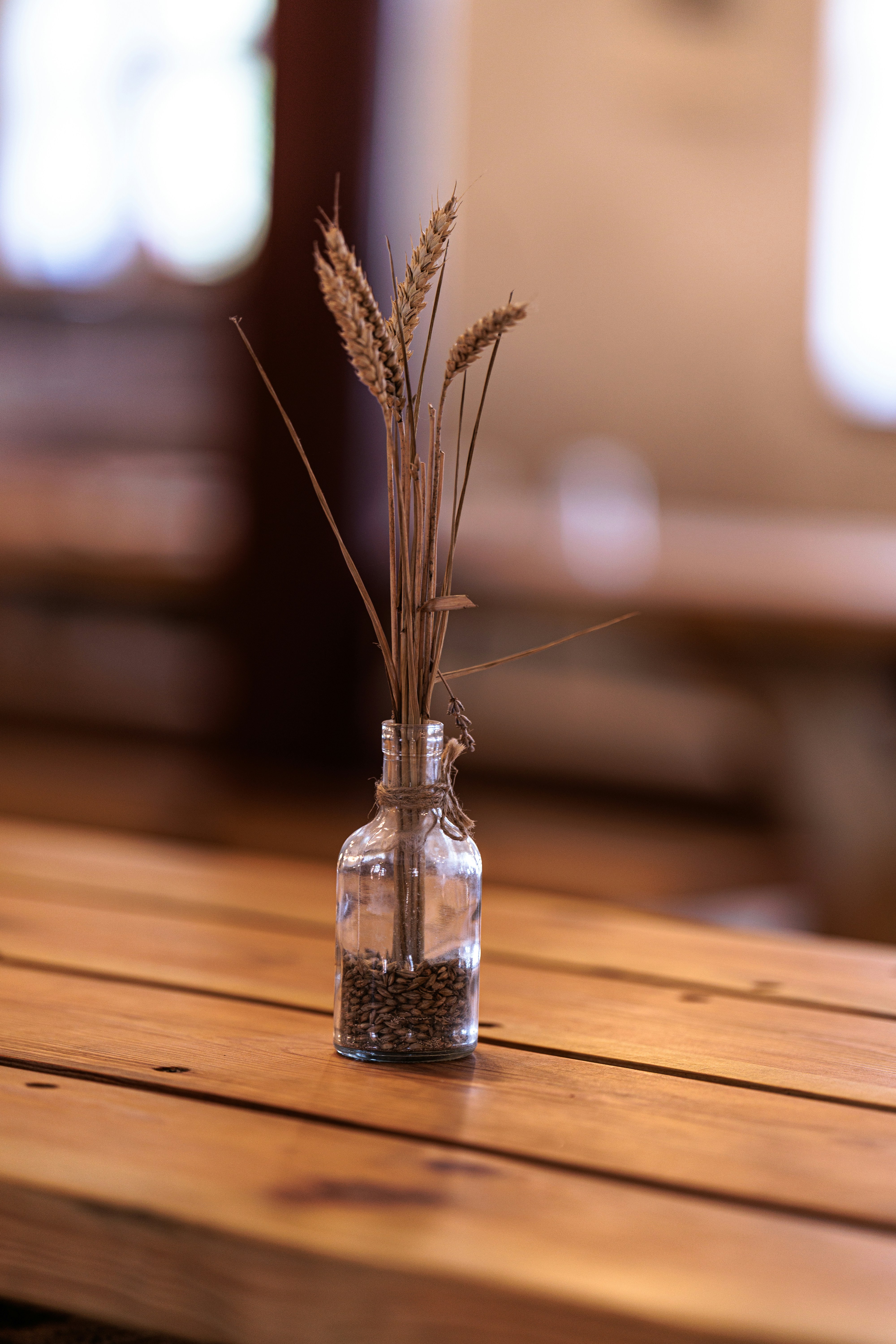 Single Wheat Accent in a Glass Vase on a Wooden Table
