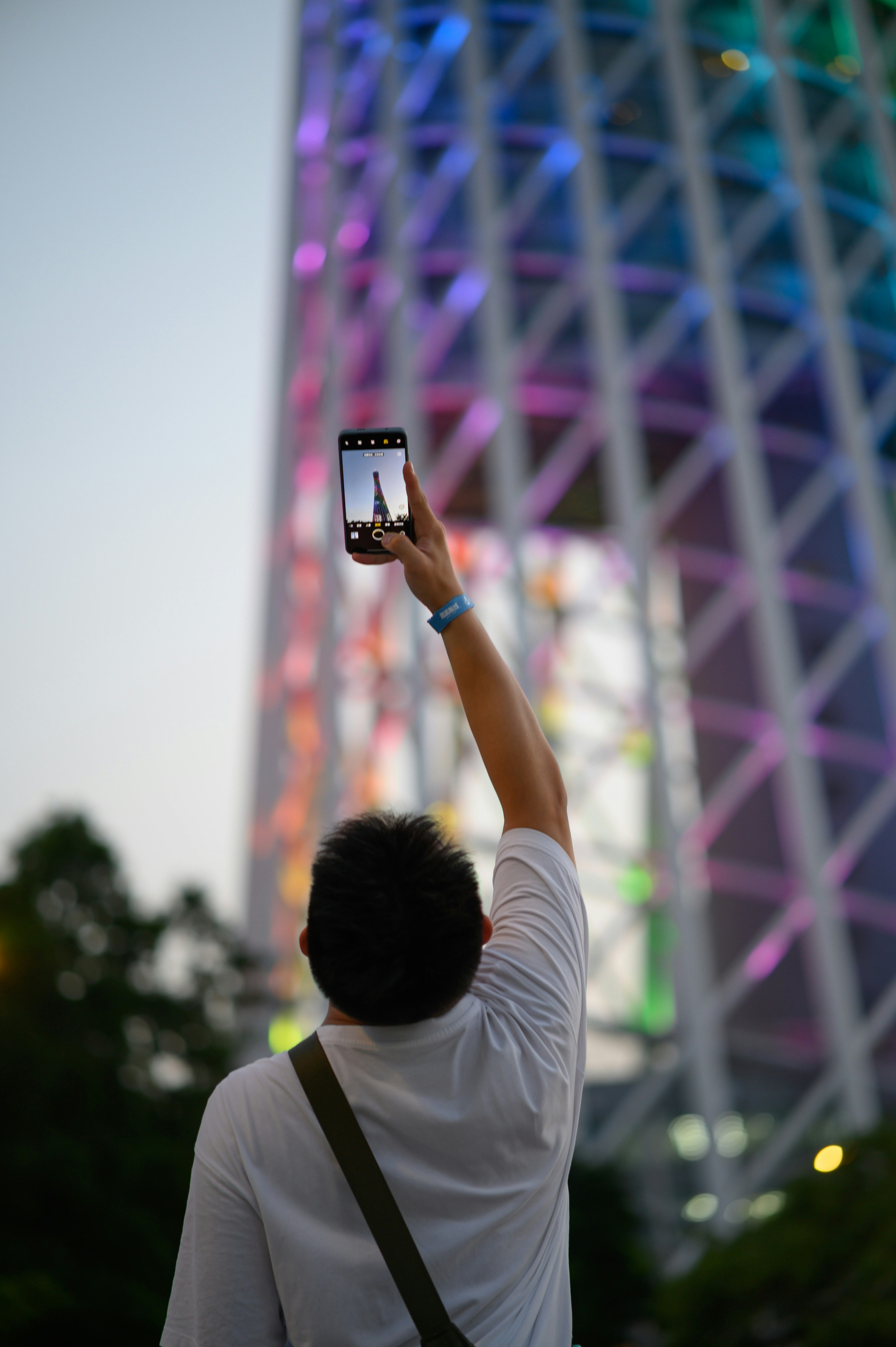 Raised Smartphone Portrait at a Neon-Tinted City Facade