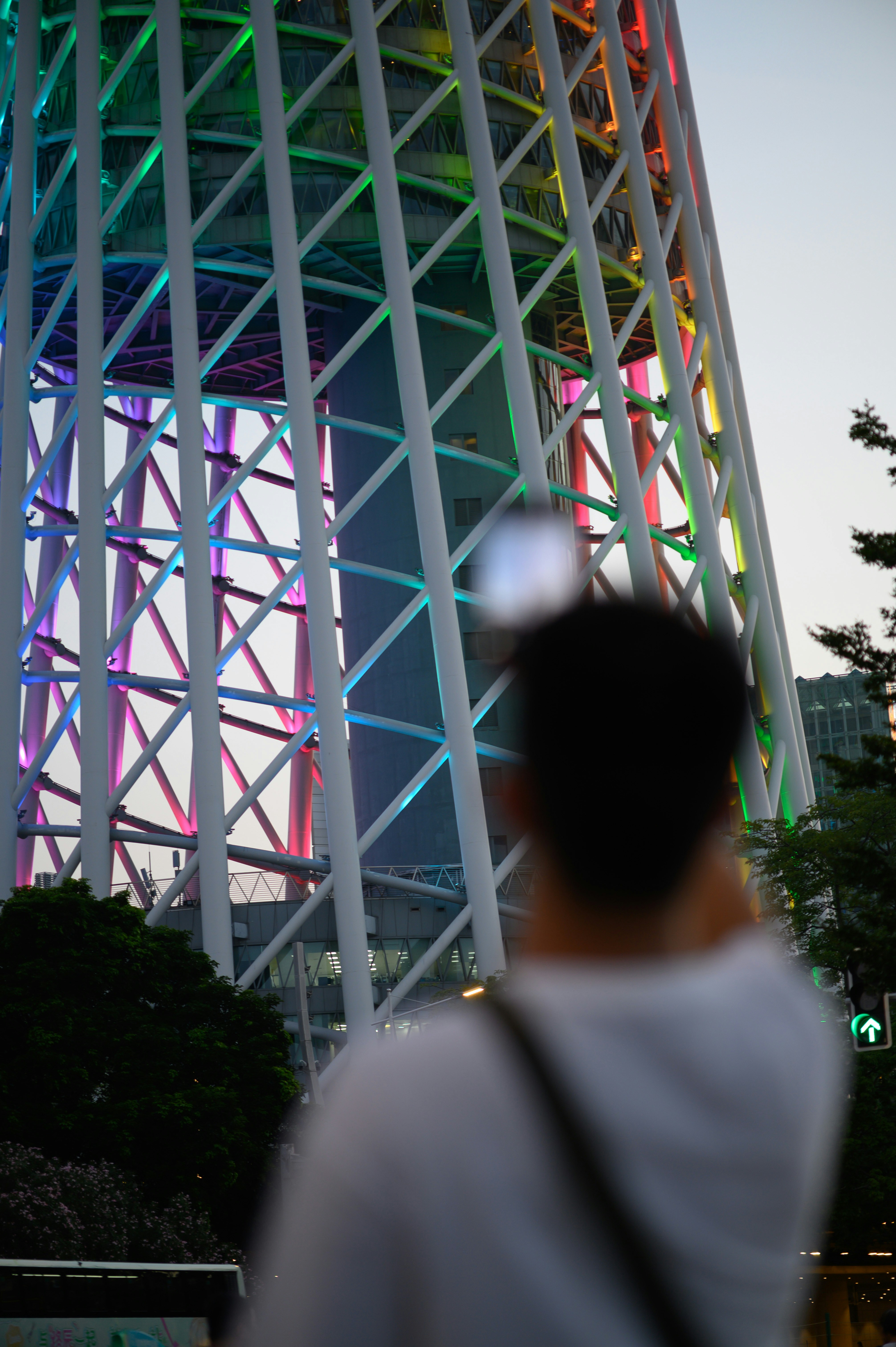 Colorful lattice tower under evening glow with a blurred observer