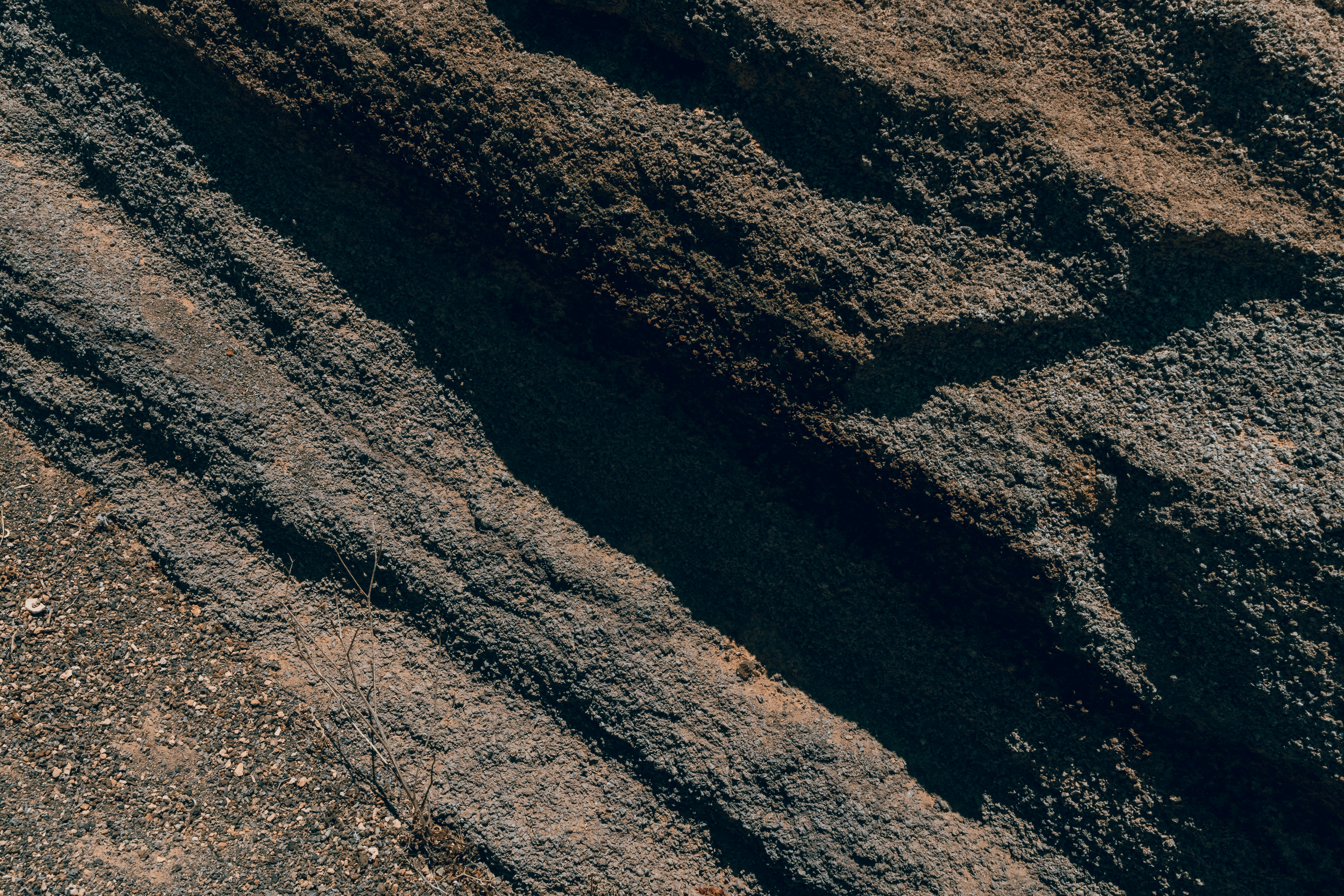 Close-up of sunlit earthen ridges and trenches revealing textured, layered soil and shadowed crevices.