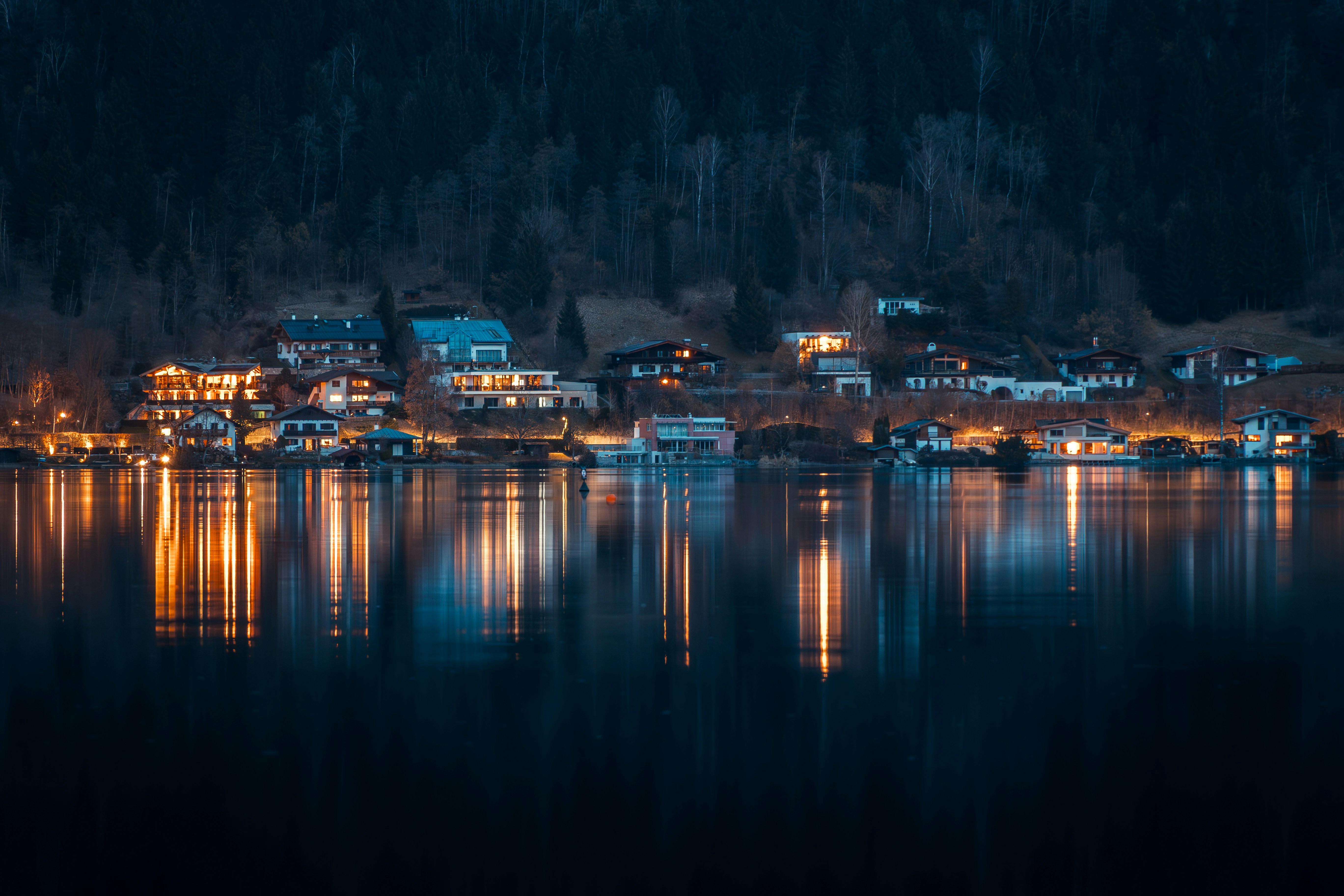 Glowing lakeside village at dusk, mirrored in still waters