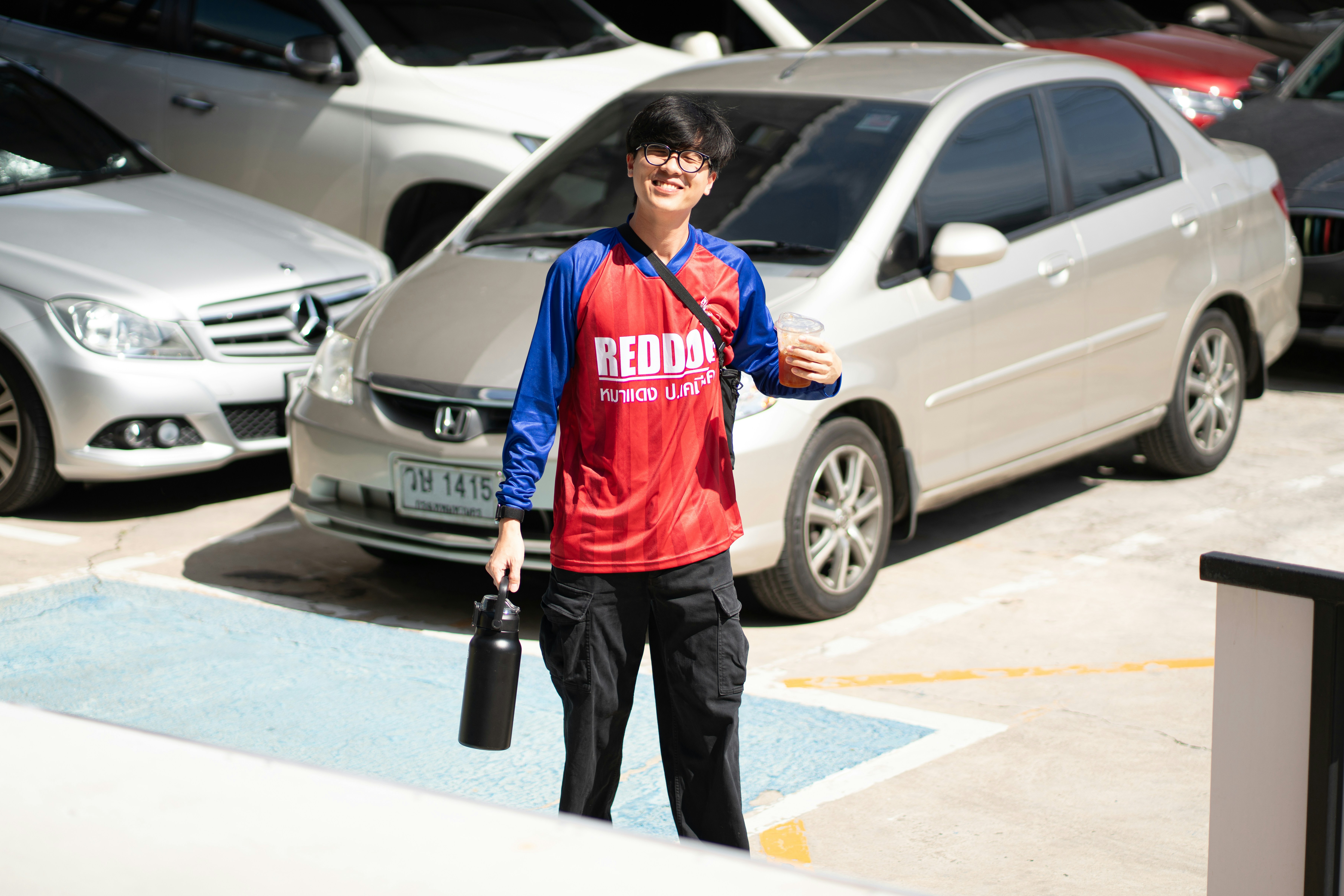 Volunteer in Red-and-Blue Jersey Amid Parking Lot bustle