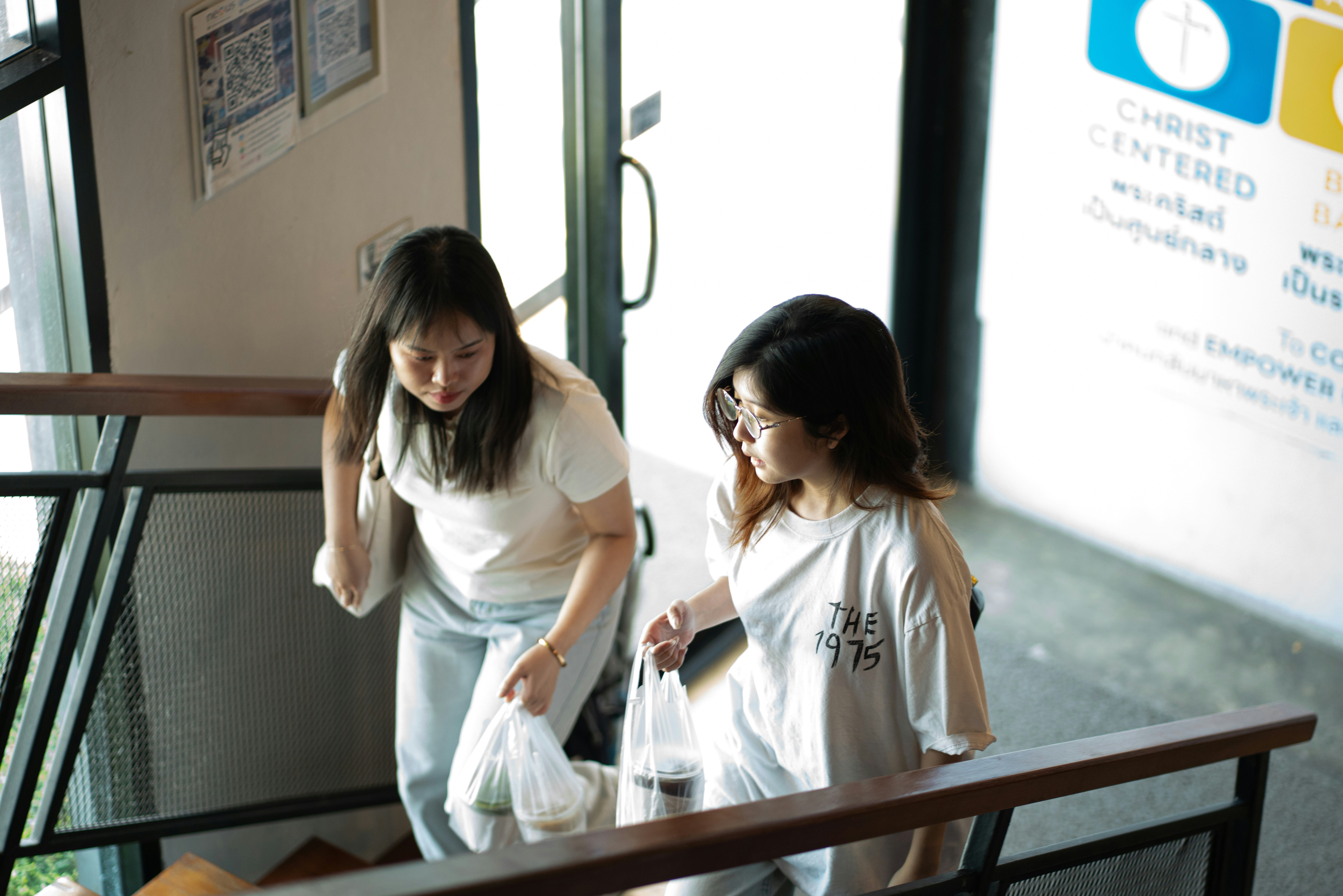 Two companions ascending the staircase with takeaway bags in hand