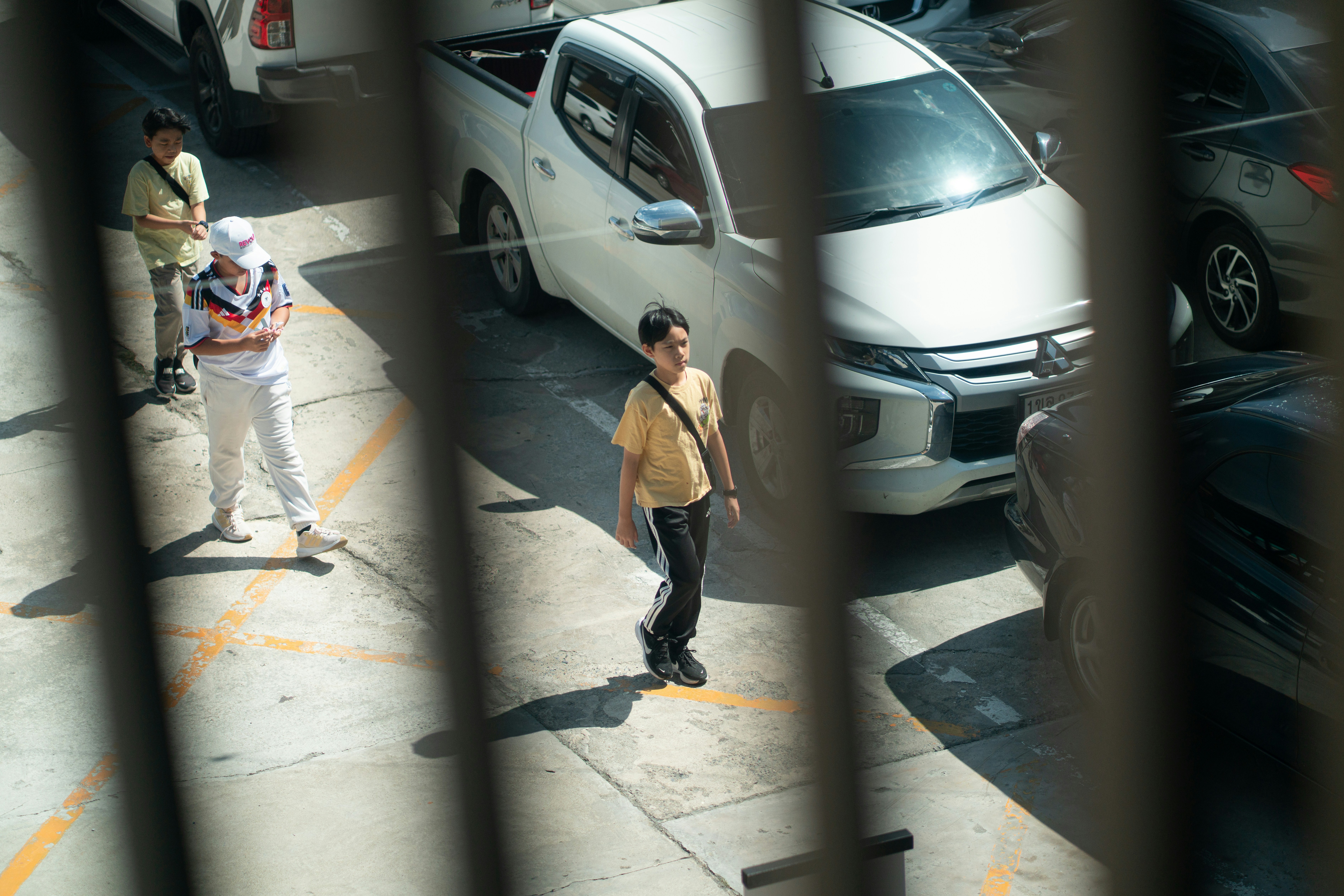 Pedestrians in a Parking Lot Framed by Vertical Bars