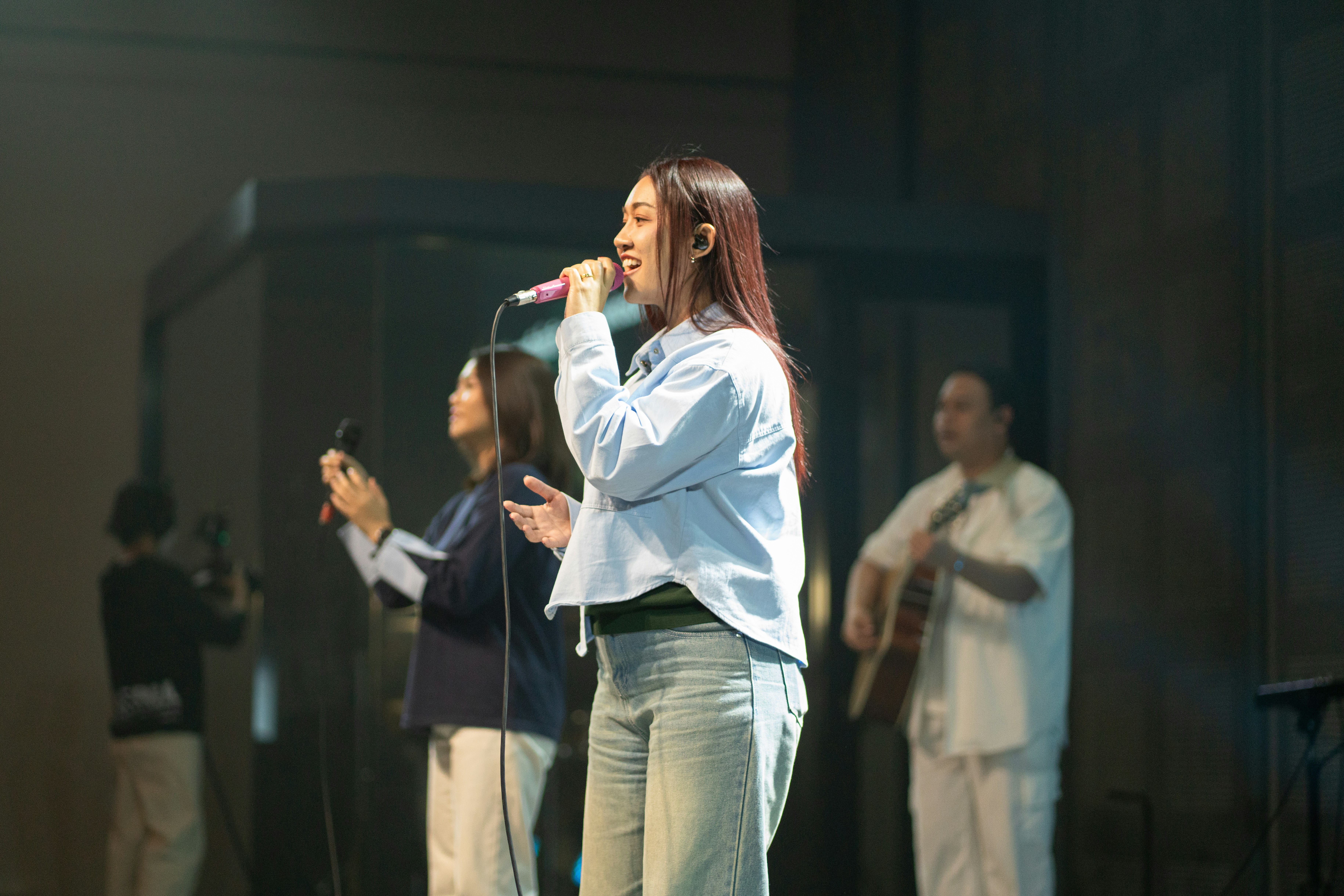 Center Stage: A vocalist in soft blue amid a band under warm stage lights