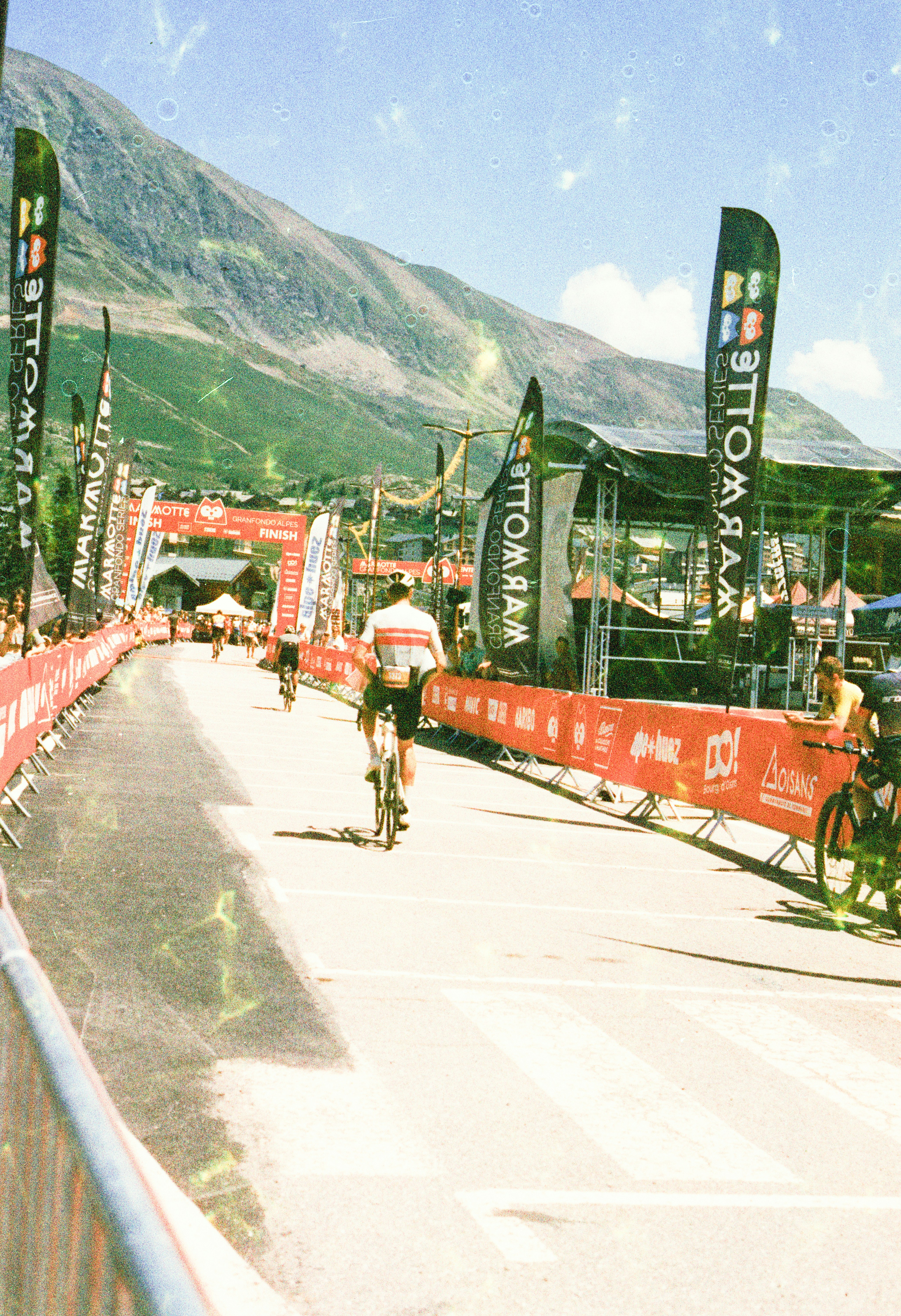 Rookie Cyclists Cross the Mountain Route Under Bannered Arc