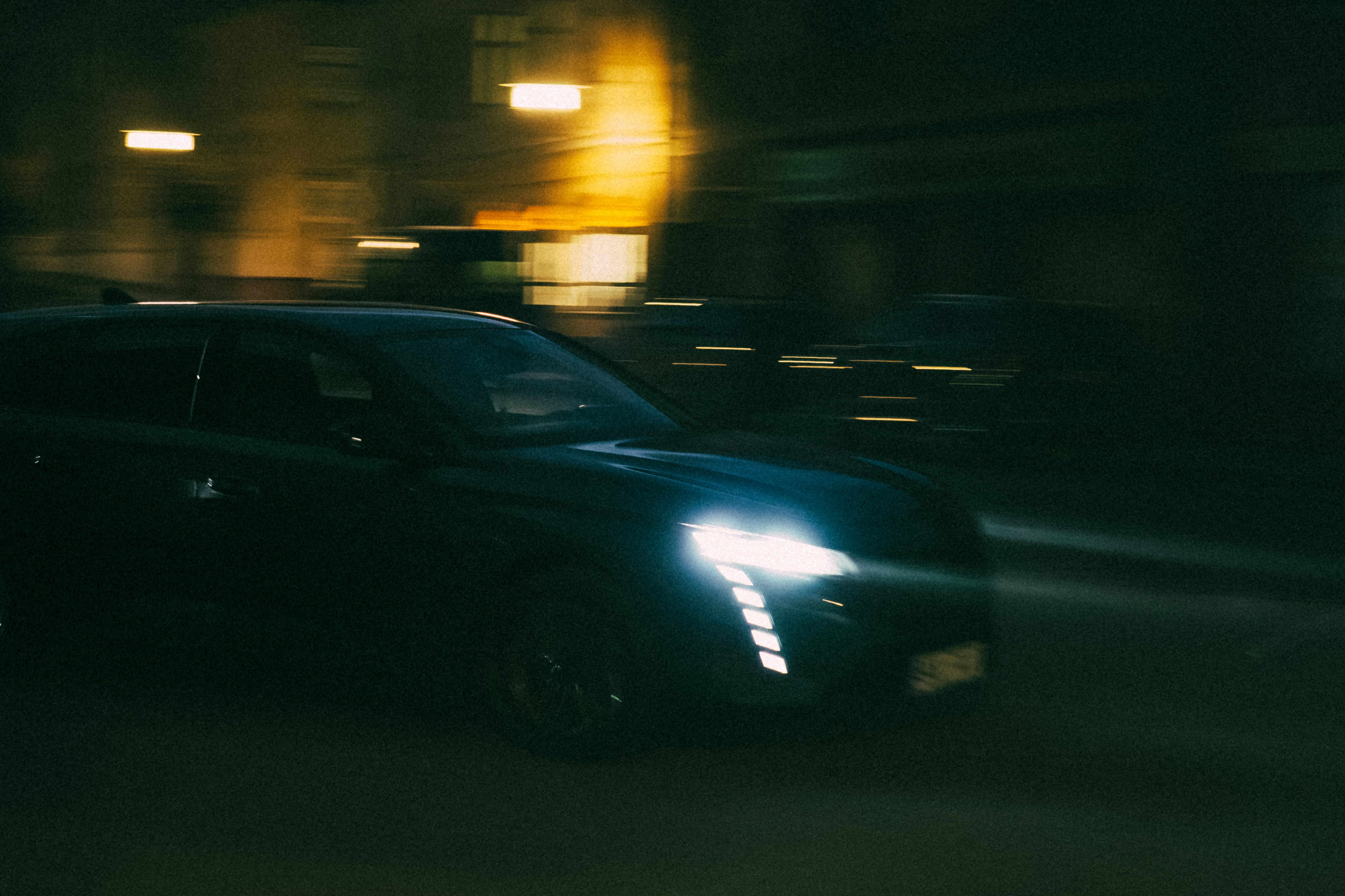 Night Run: A Blurred Black SUV Streaks by with Bright Front Lamps