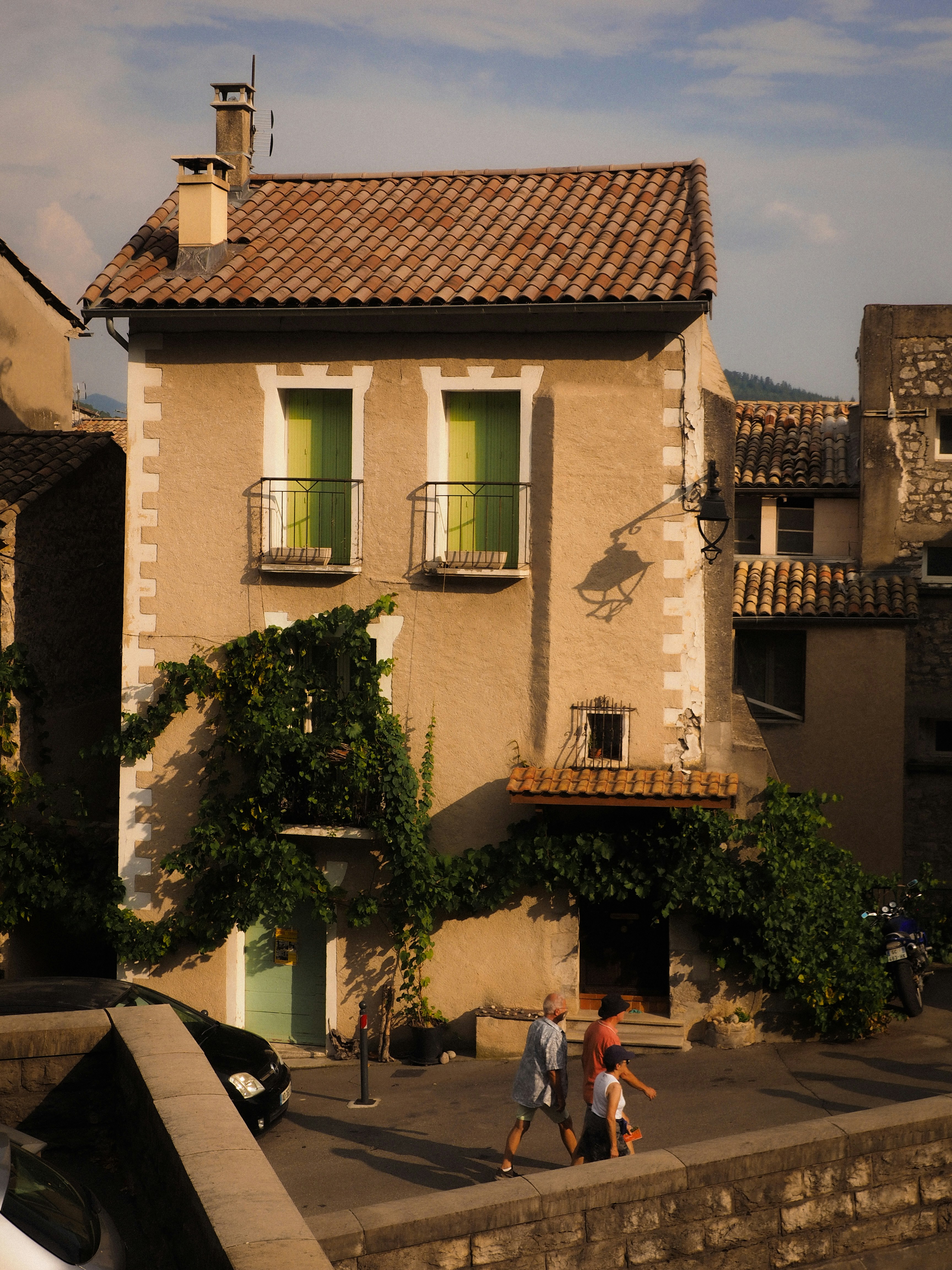 Sunlit Facade with Ivy and Passing Travelers