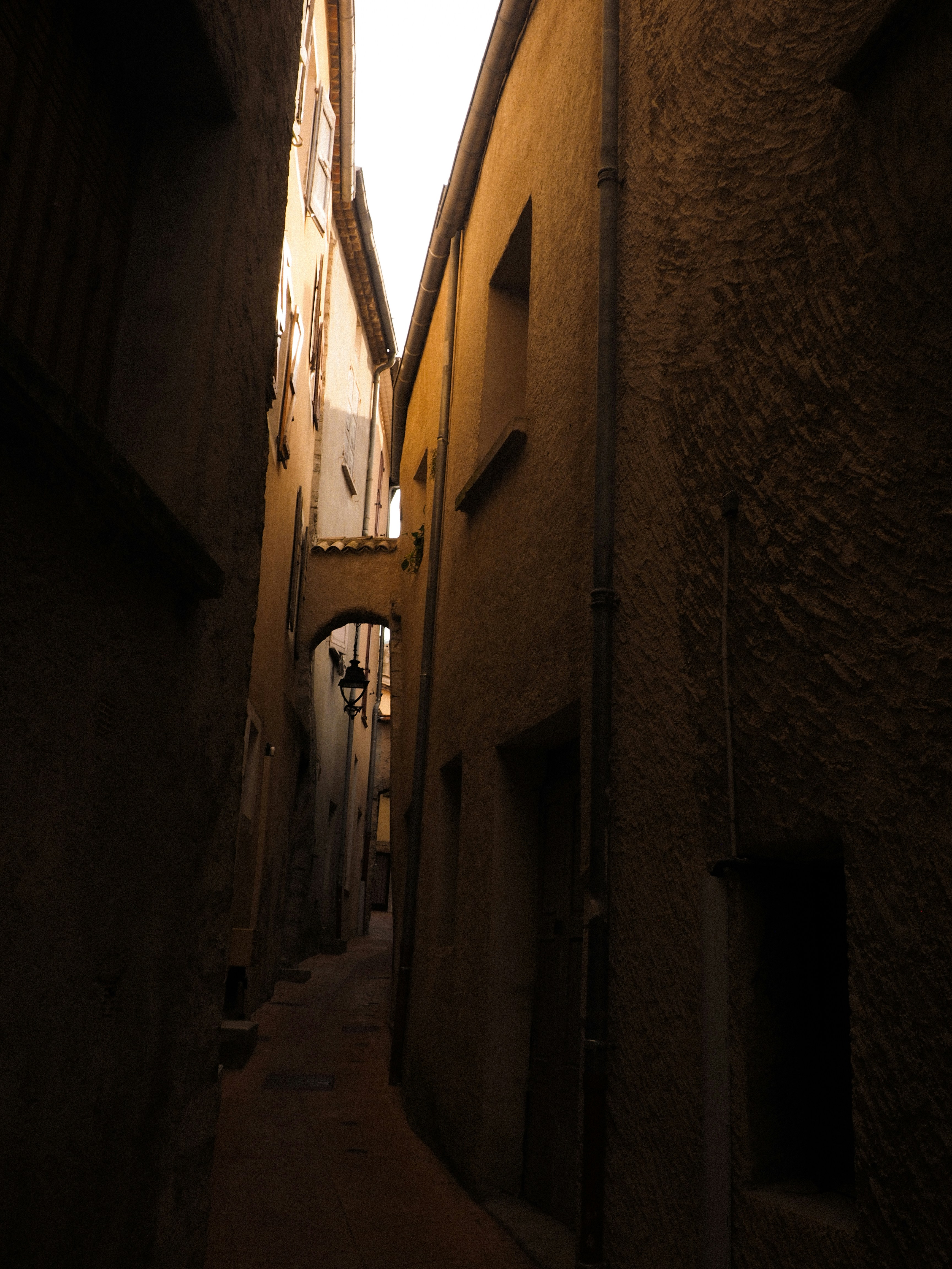 Sunlit Gap: A Narrow European Alley Between Weathered Walls