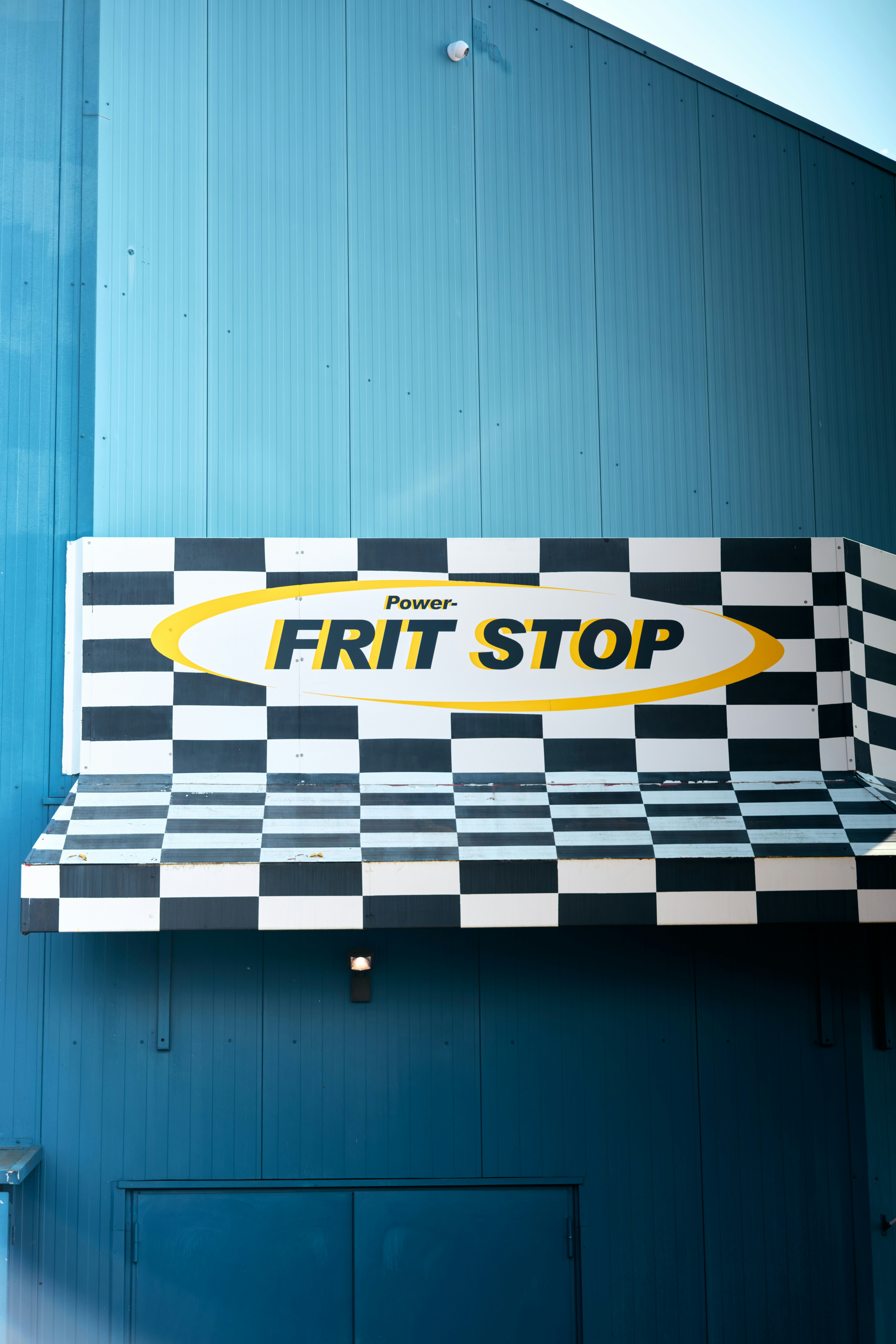 Faded Blue Facade Meets Checkerboard Sign